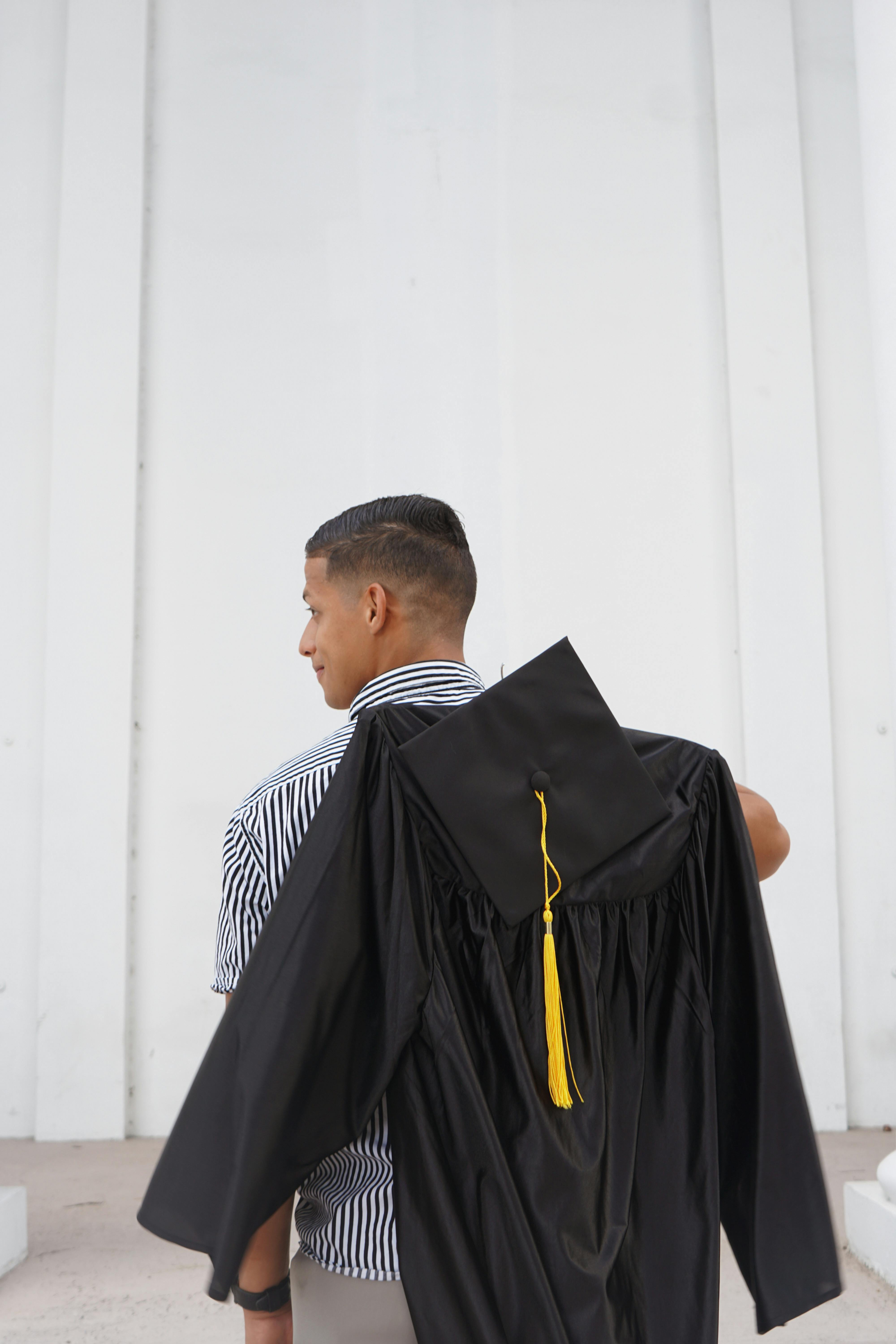 Back View of a Man Holding a Graduation Gown and a Mortarboard · Free ...