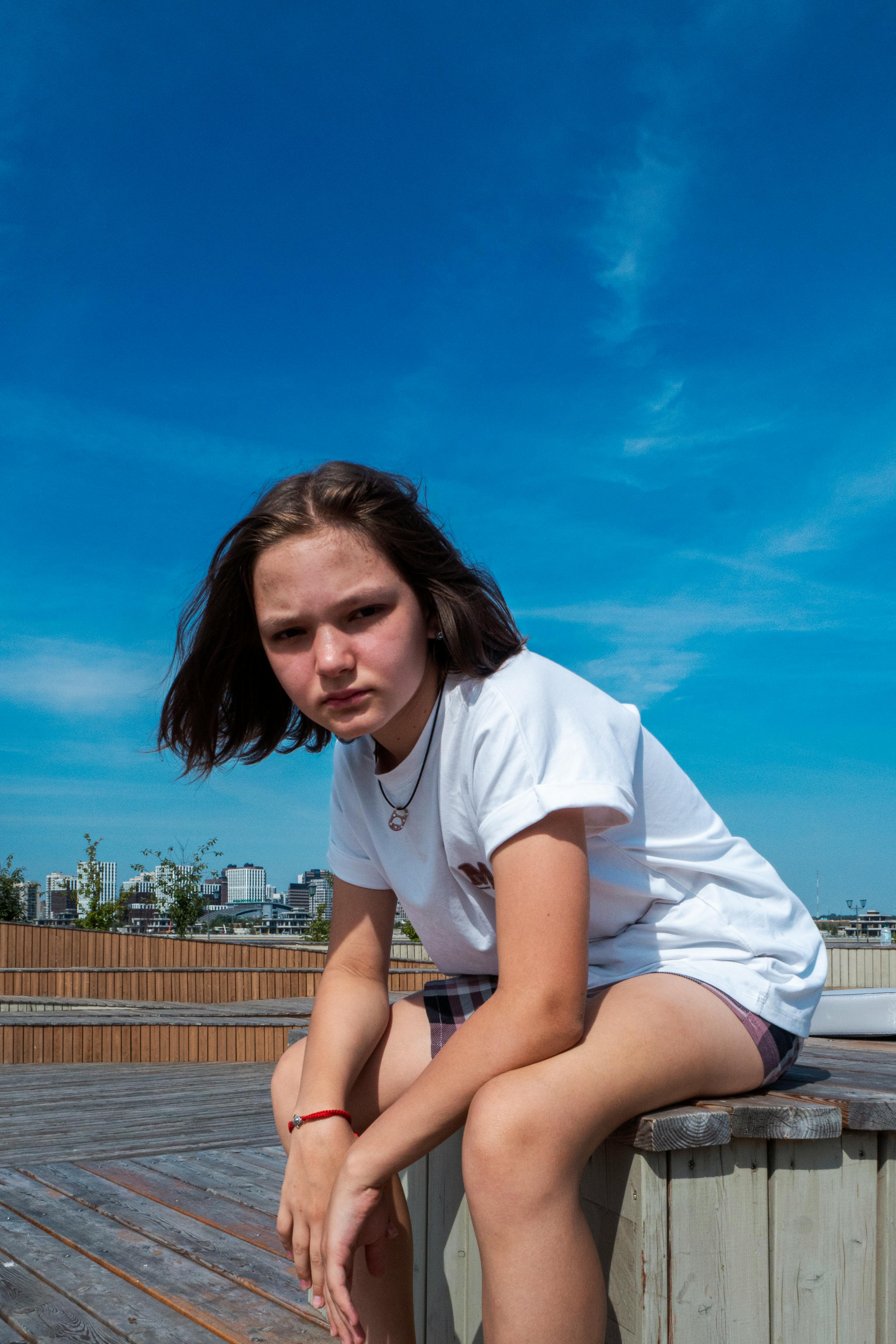 A Young Girl Sitting on a Wooden Bench Outside in Summer · Free Stock Photo