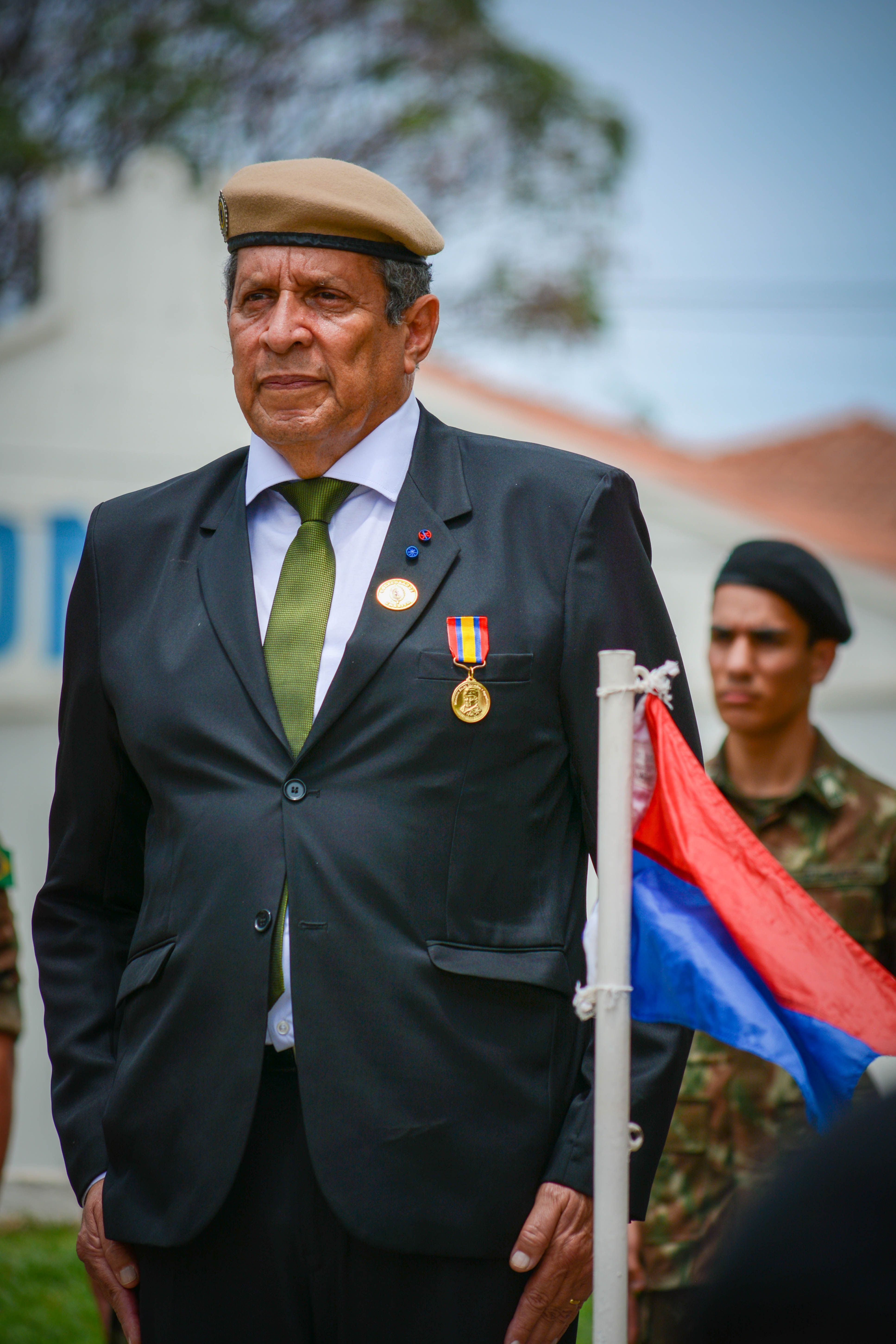A Man in a Suit Wearing a Badge and a Man in a Uniform at a Ceremony ...