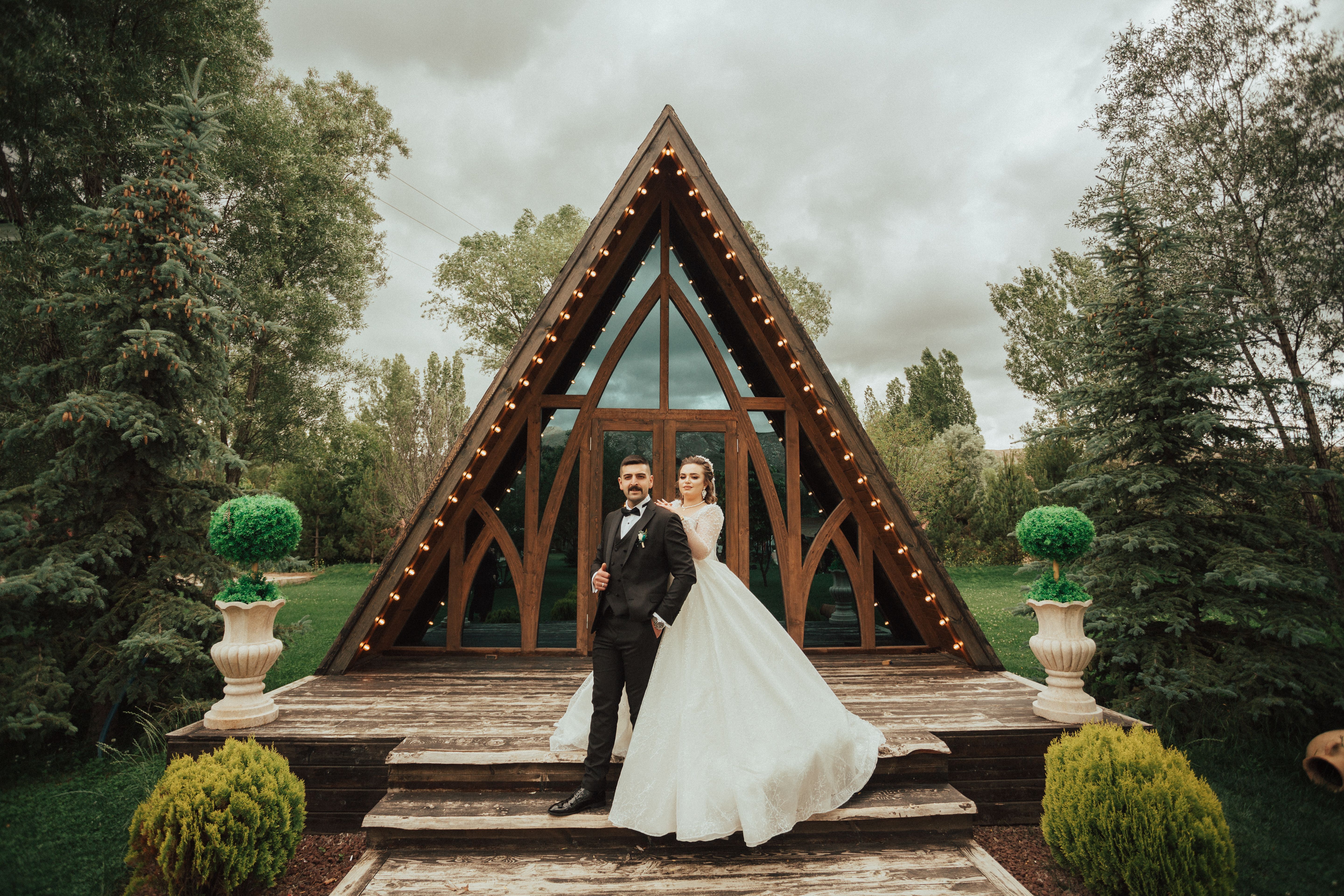 Newlyweds Posing by Wooden House · Free Stock Photo