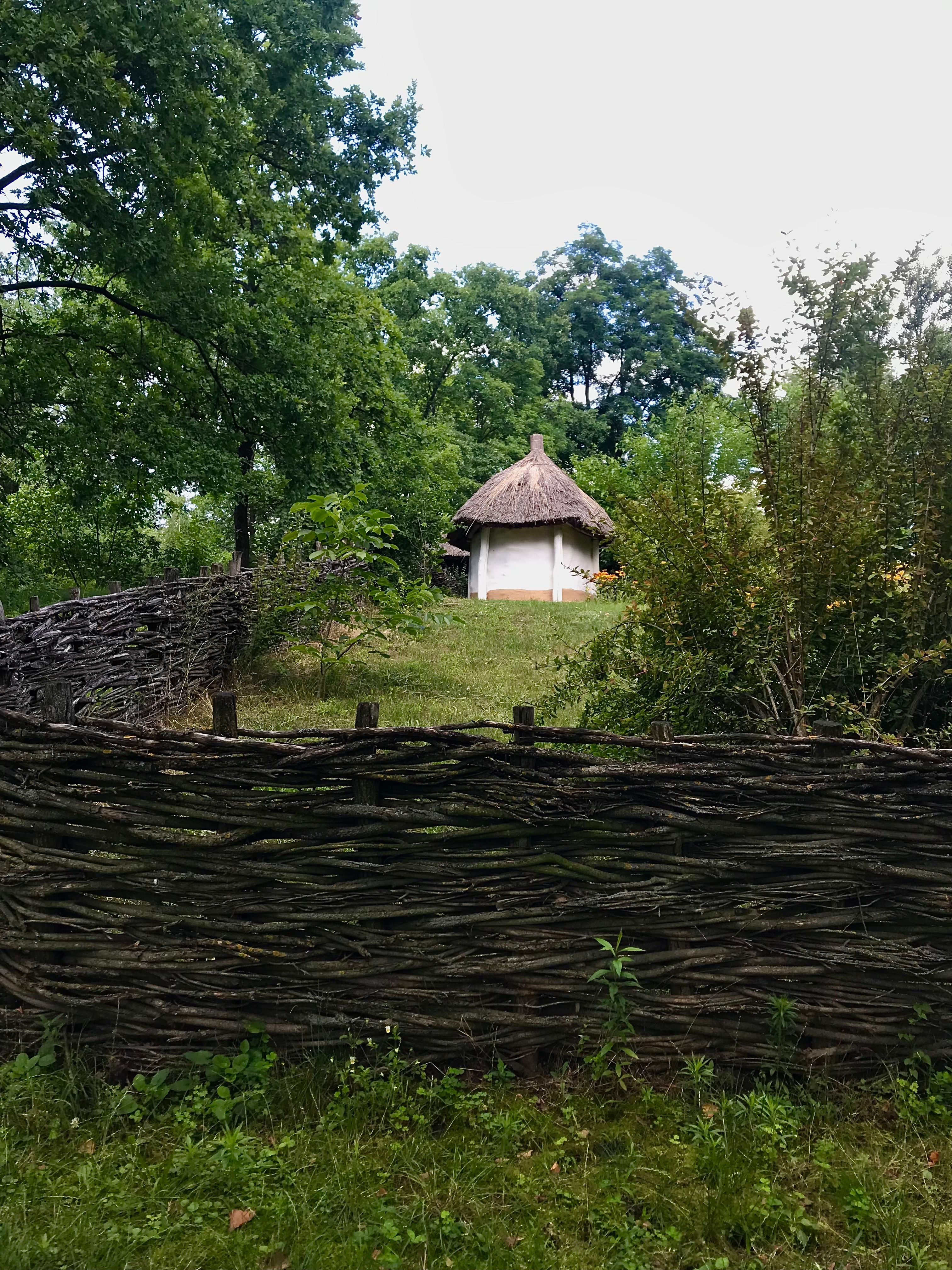 Hut with Straw Roof on Hill Surrounded by Wooden Fence · Free Stock Photo