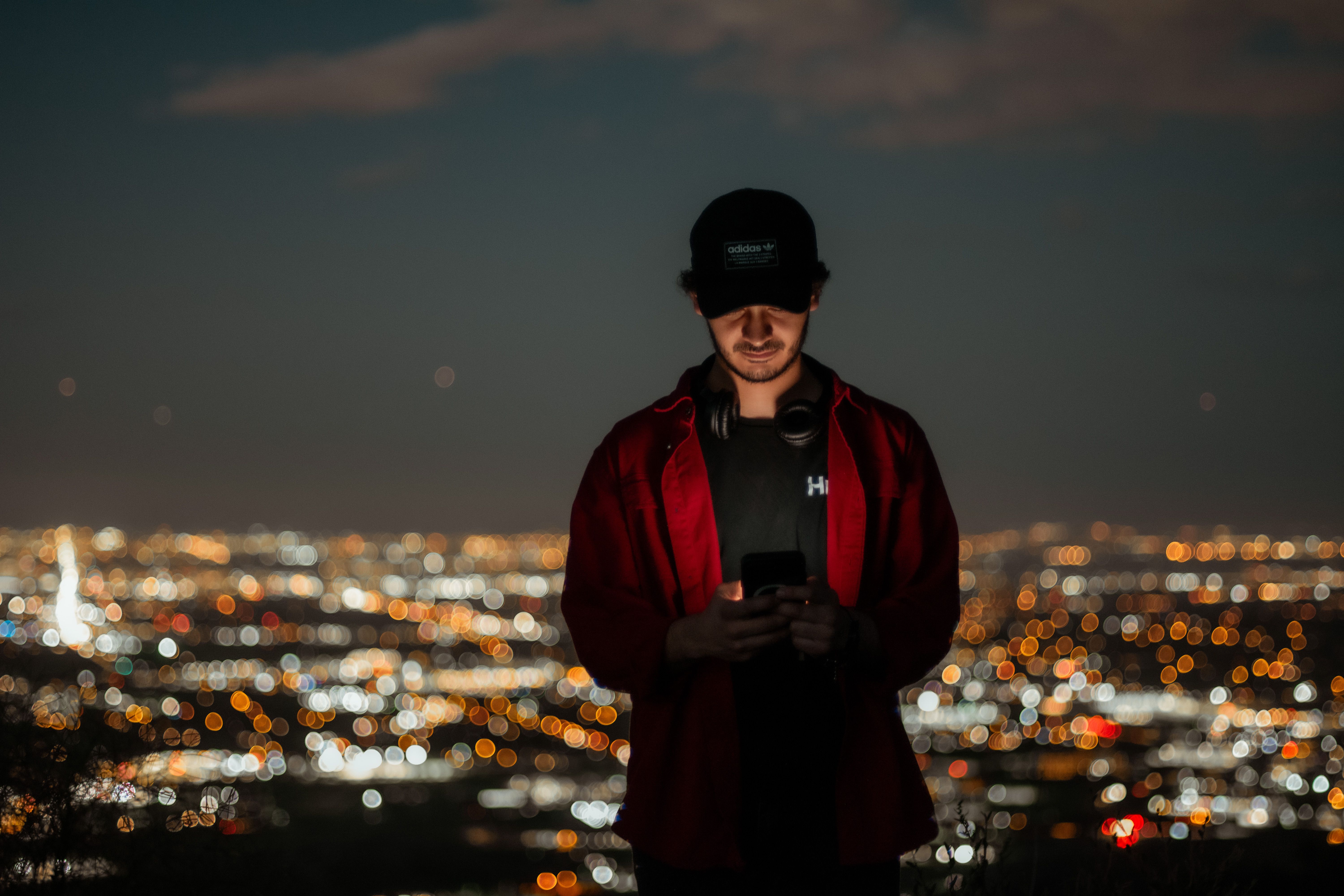 Man with Smartphone against Illuminated Night Cityscape · Free Stock Photo
