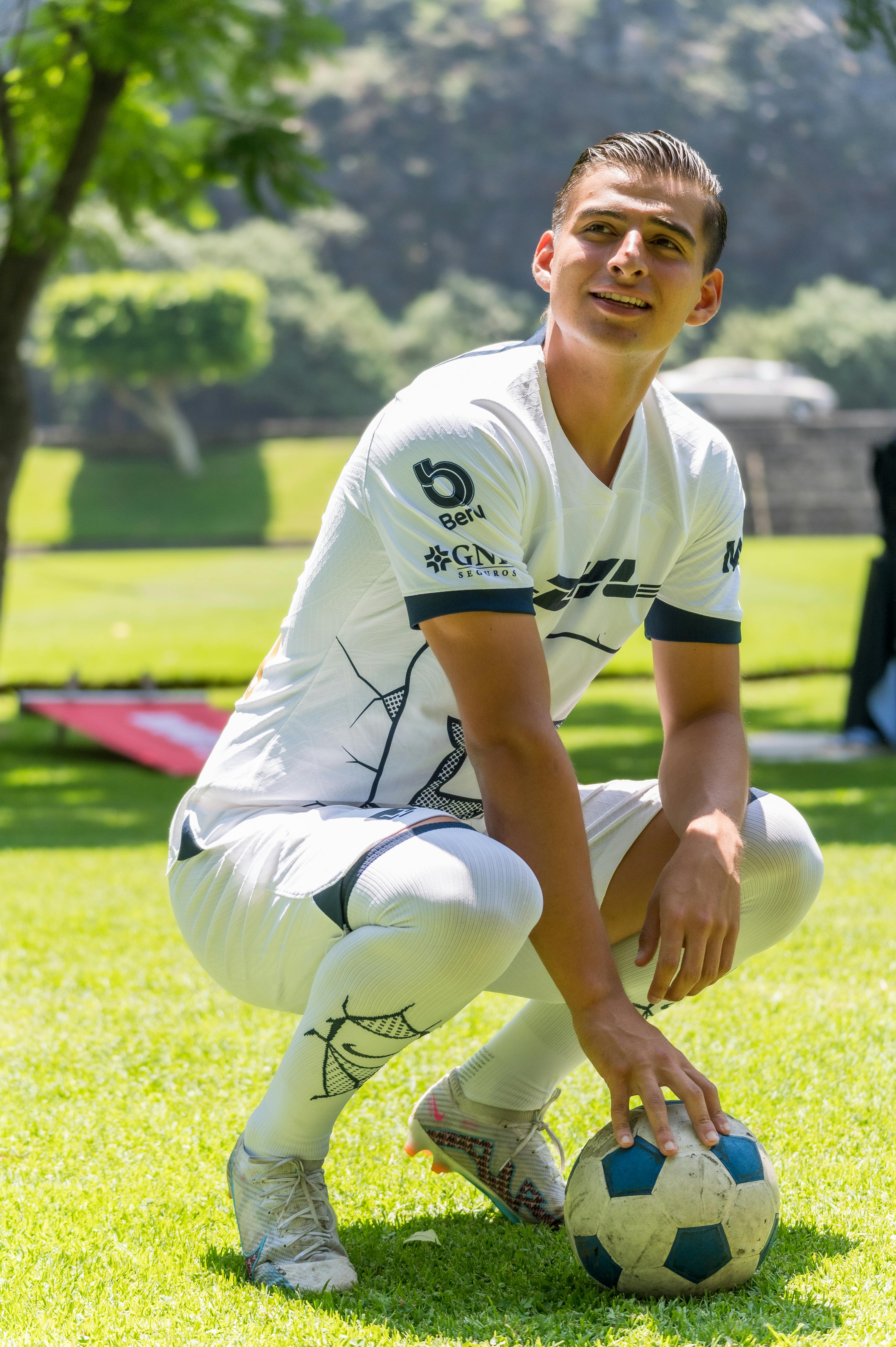 Smiling Football Player Crouching Next to a Ball · Free Stock Photo