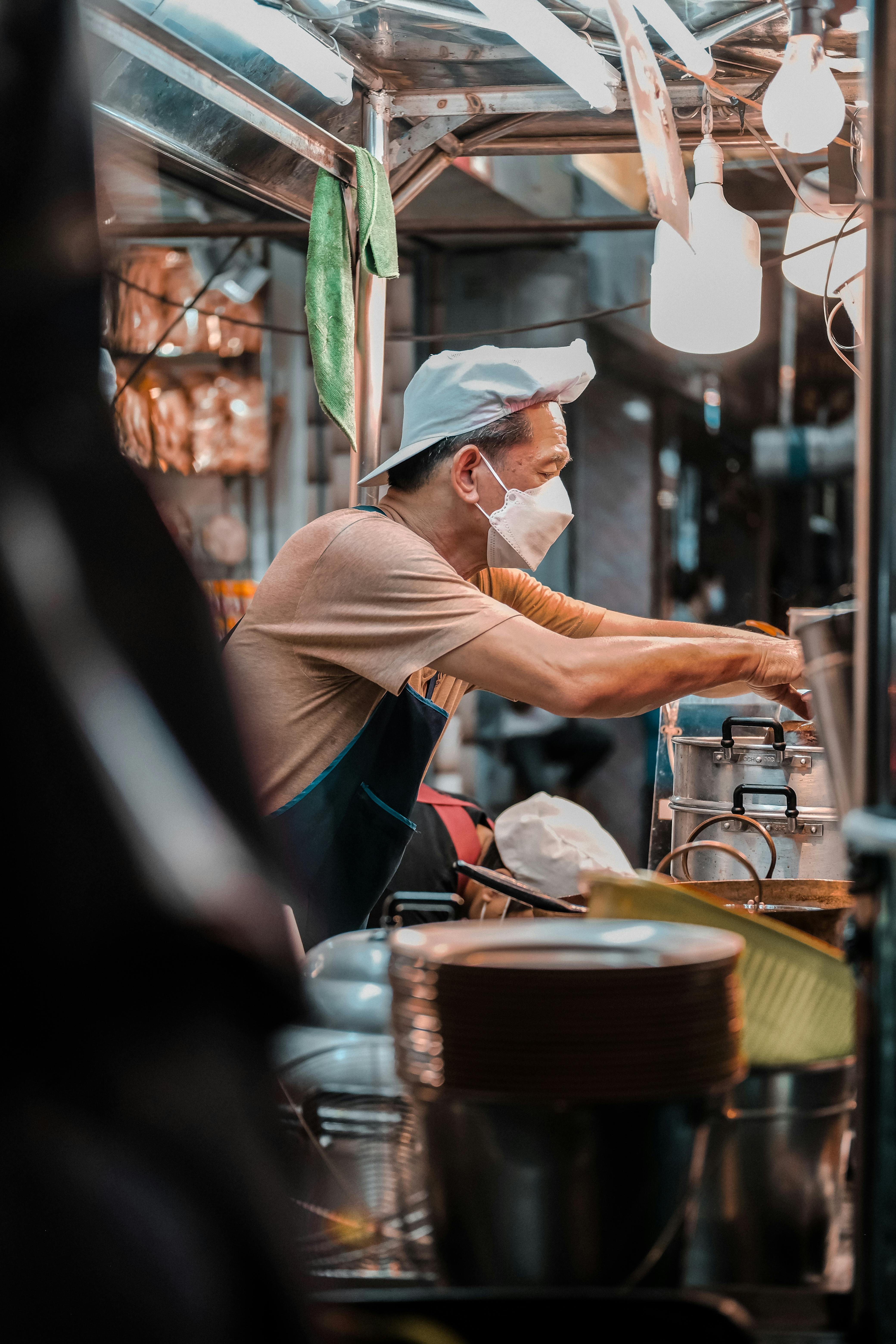 Cook in a Face Mask Preparing Food at a Street Stall · Free Stock Photo