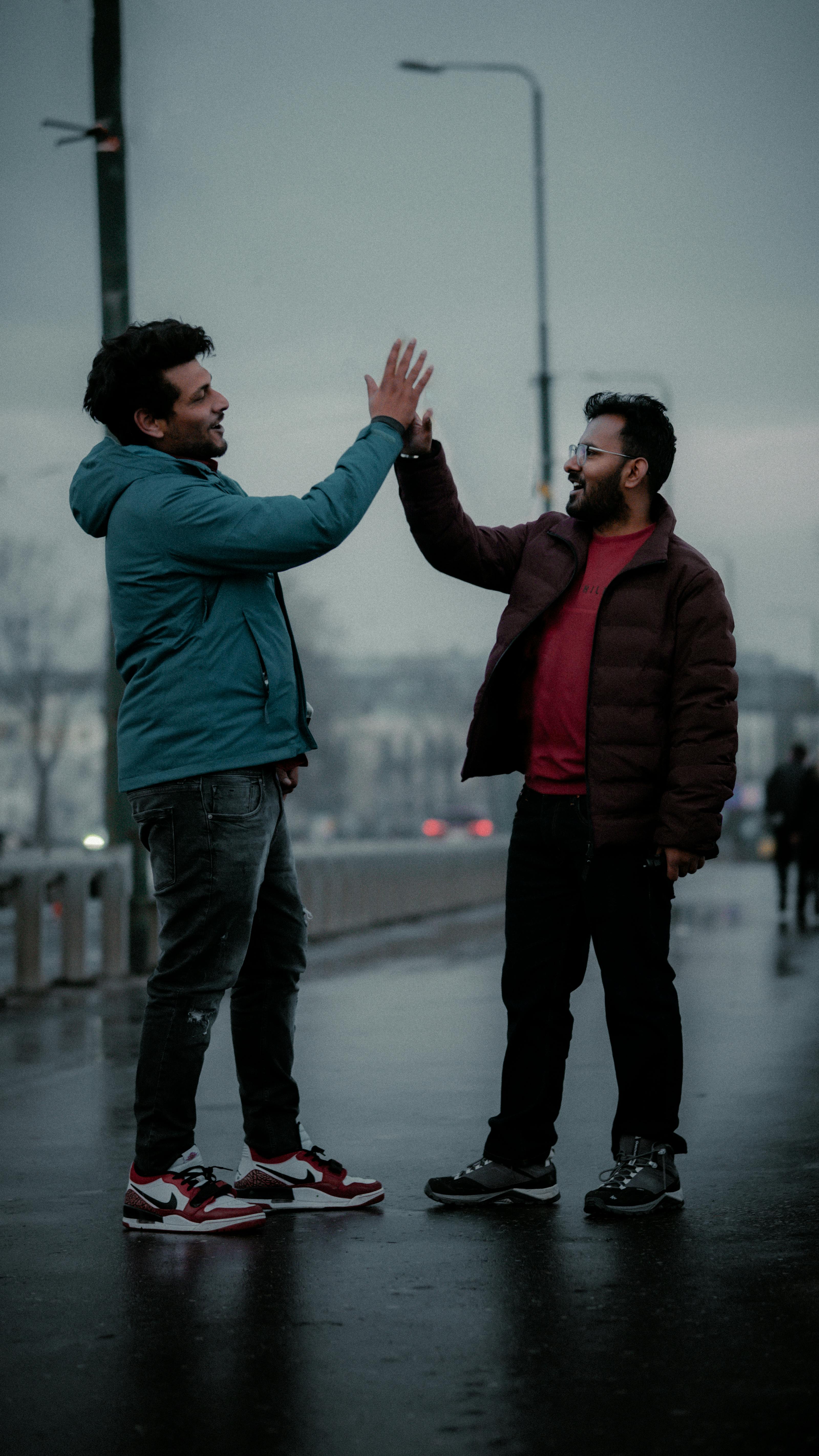 Two men high five each other in the rain · Free Stock Photo