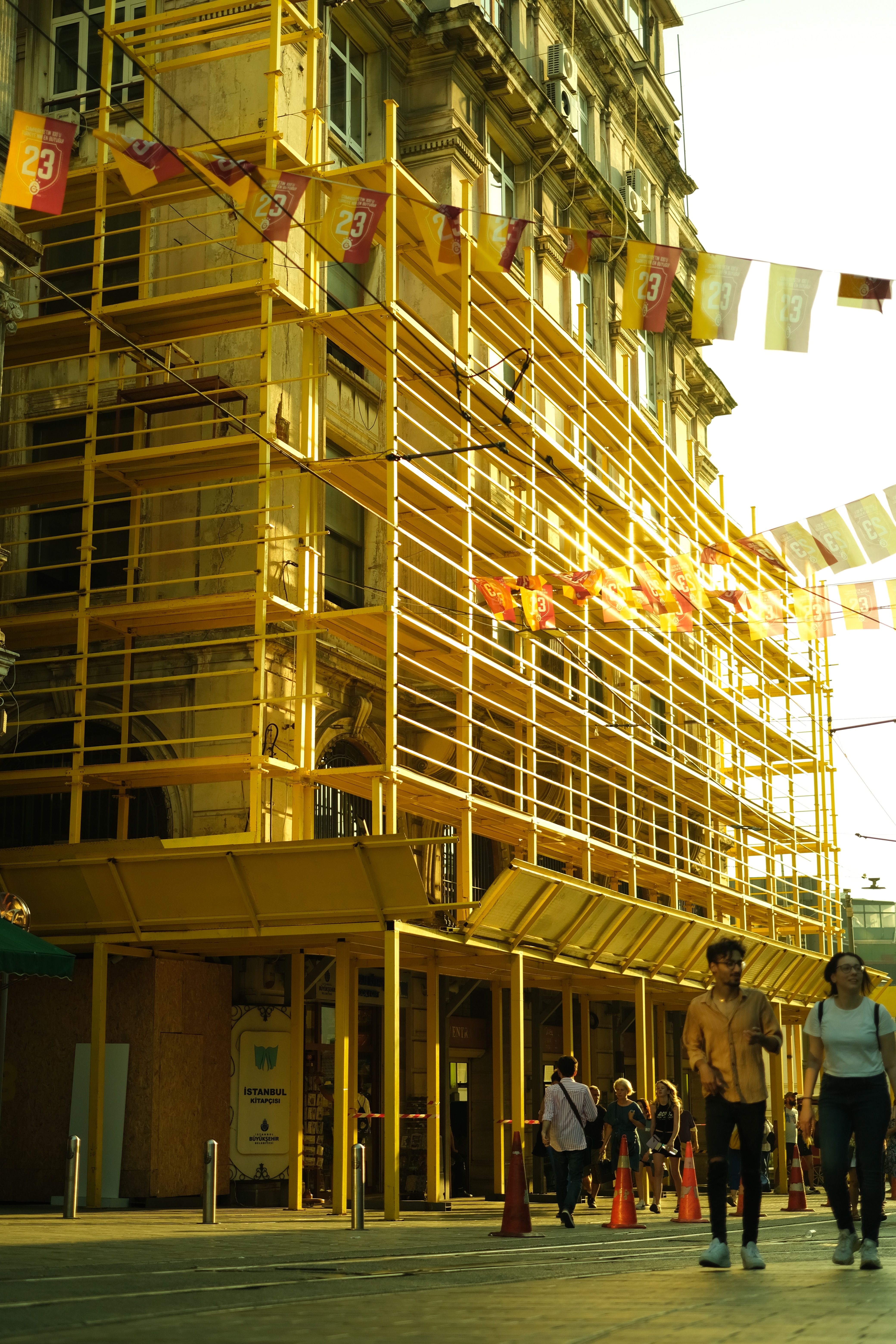 People Walking on a Street by a Building with Scaffolding Attached ...