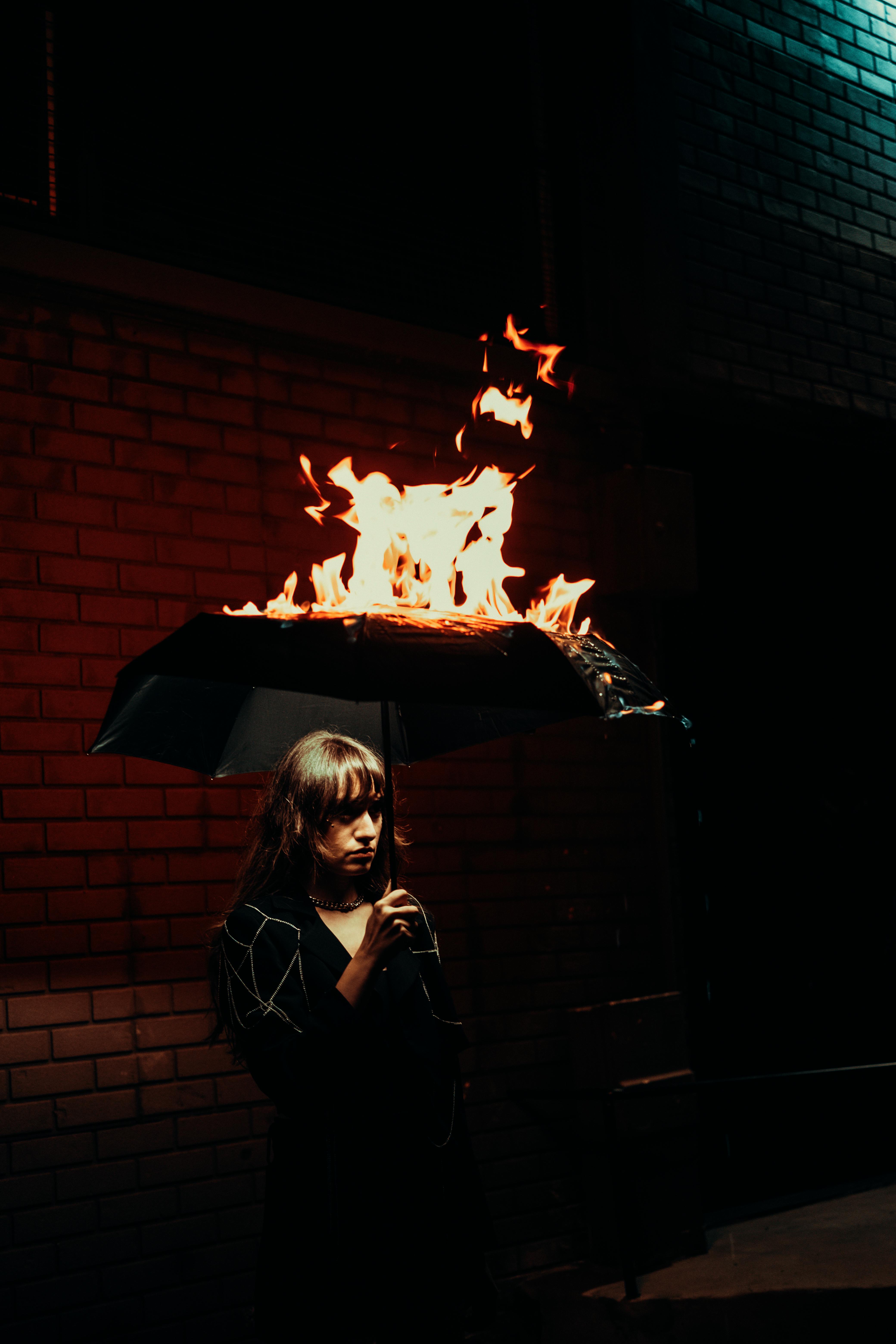 Young Woman Standing on a Night Street Under a Burning Umbrella · Free Stock Photo