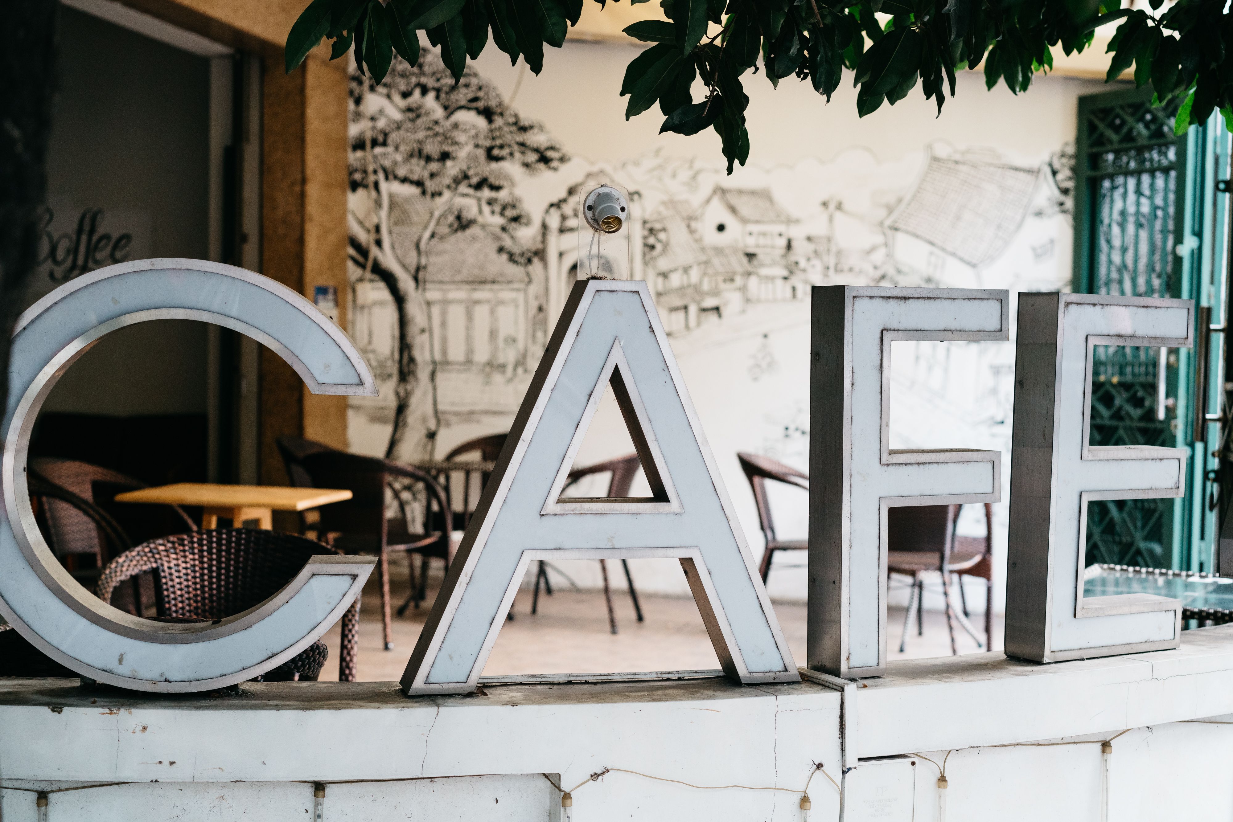 A cafe sign with the word cafe in front of it · Free Stock Photo