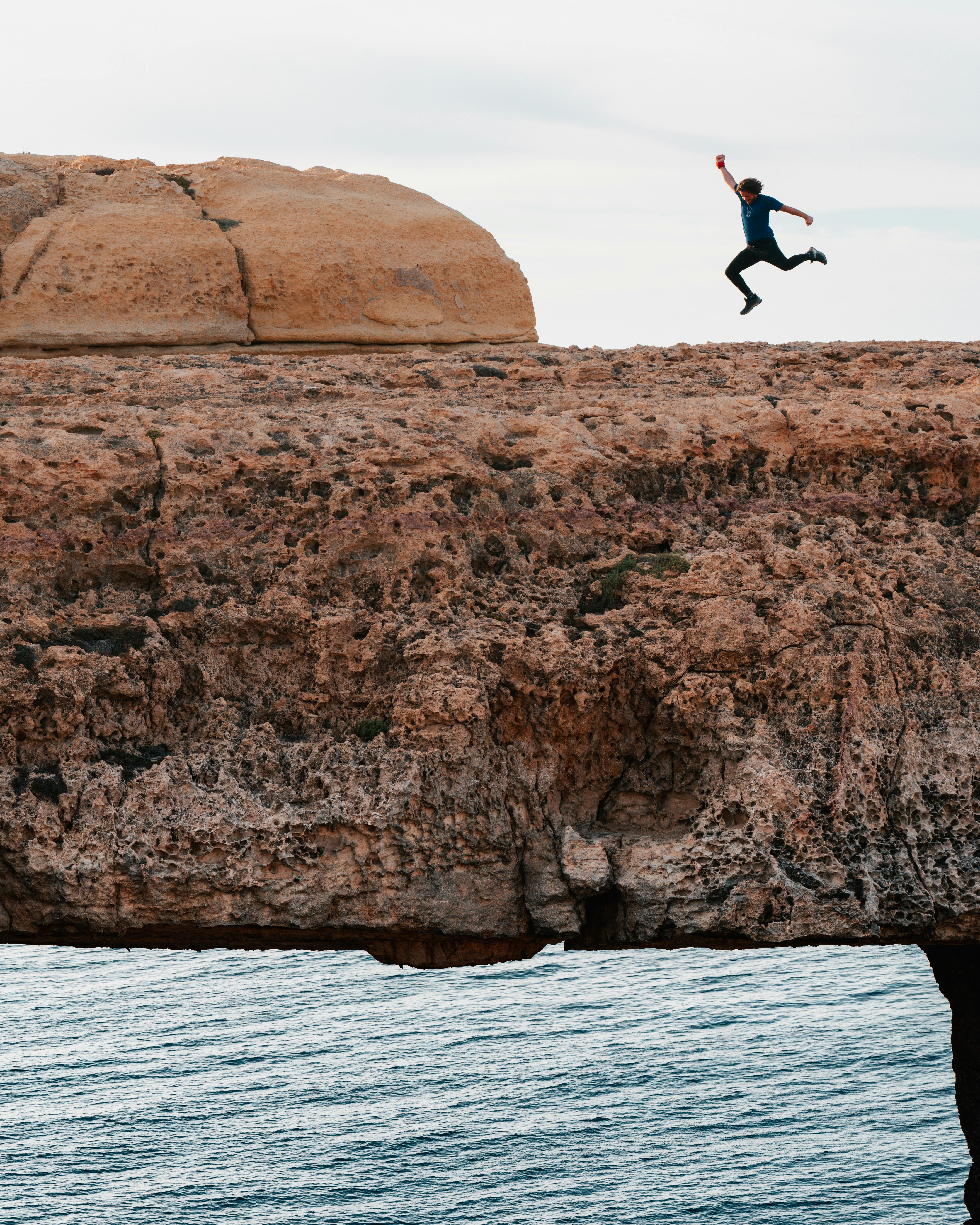 Man Jumping over Rocks on Sea Shore · Free Stock Photo