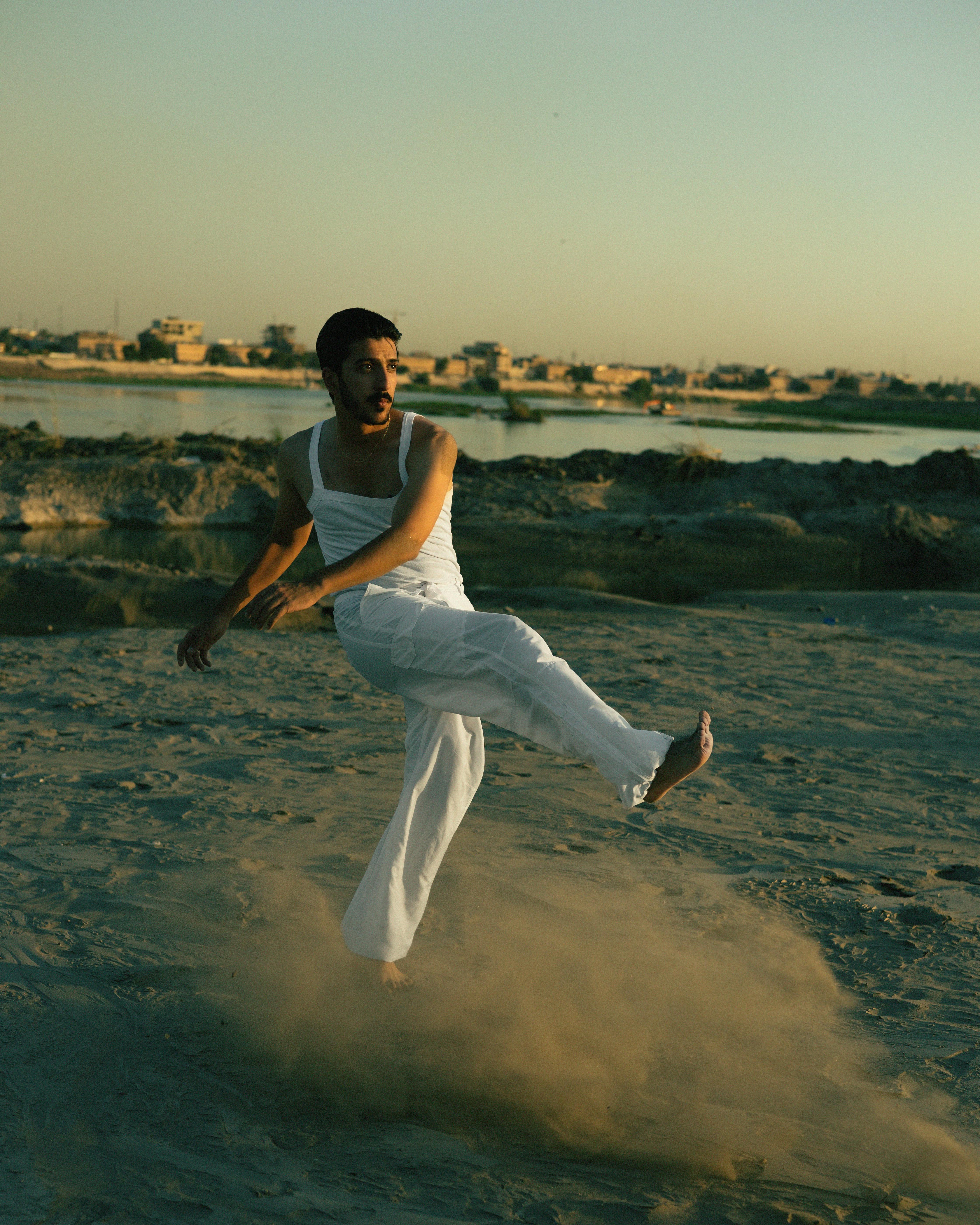 Young Man Kicking up Sand on the Beach · Free Stock Photo