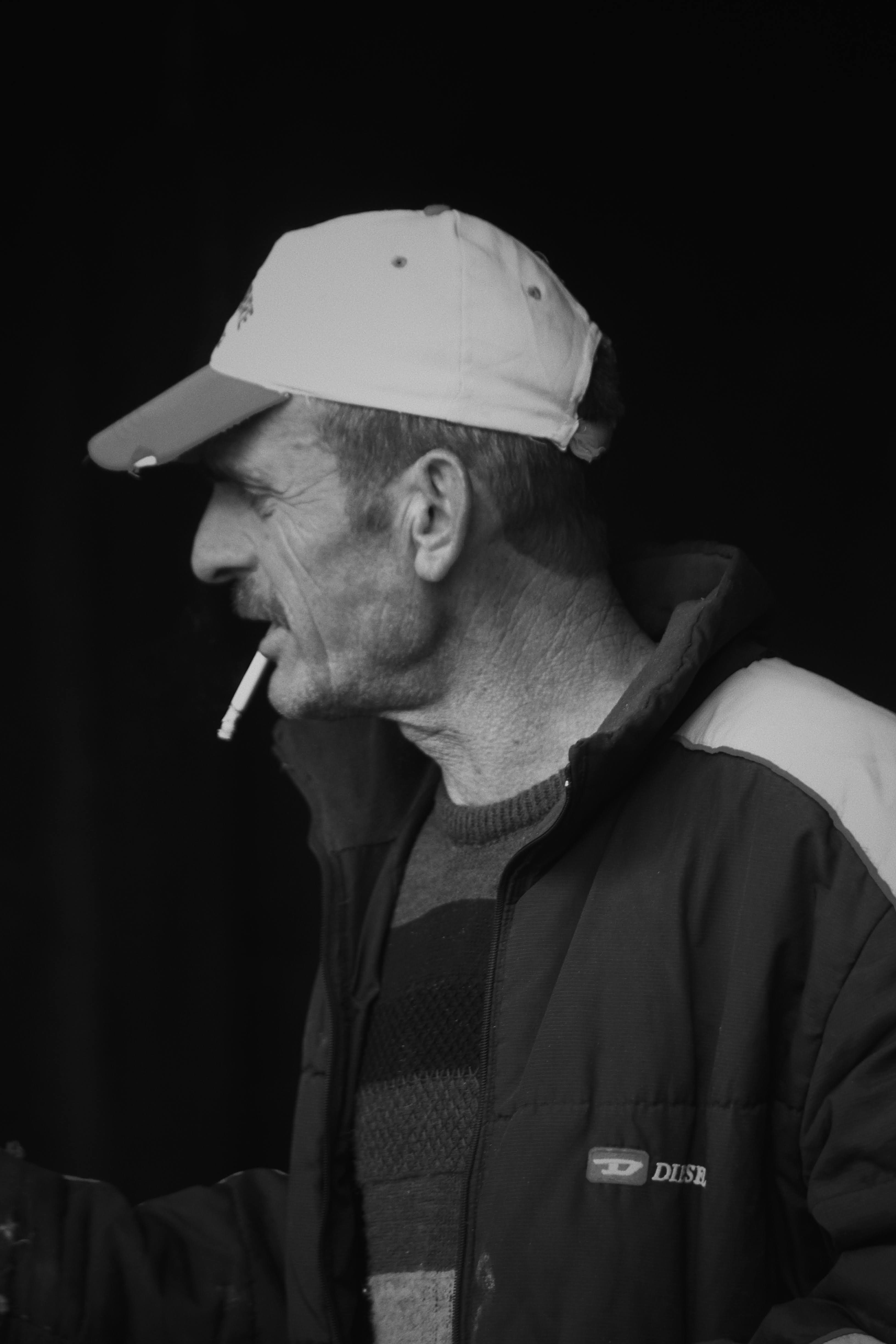Man in Cap Smoking Cigarette in Black and White · Free Stock Photo