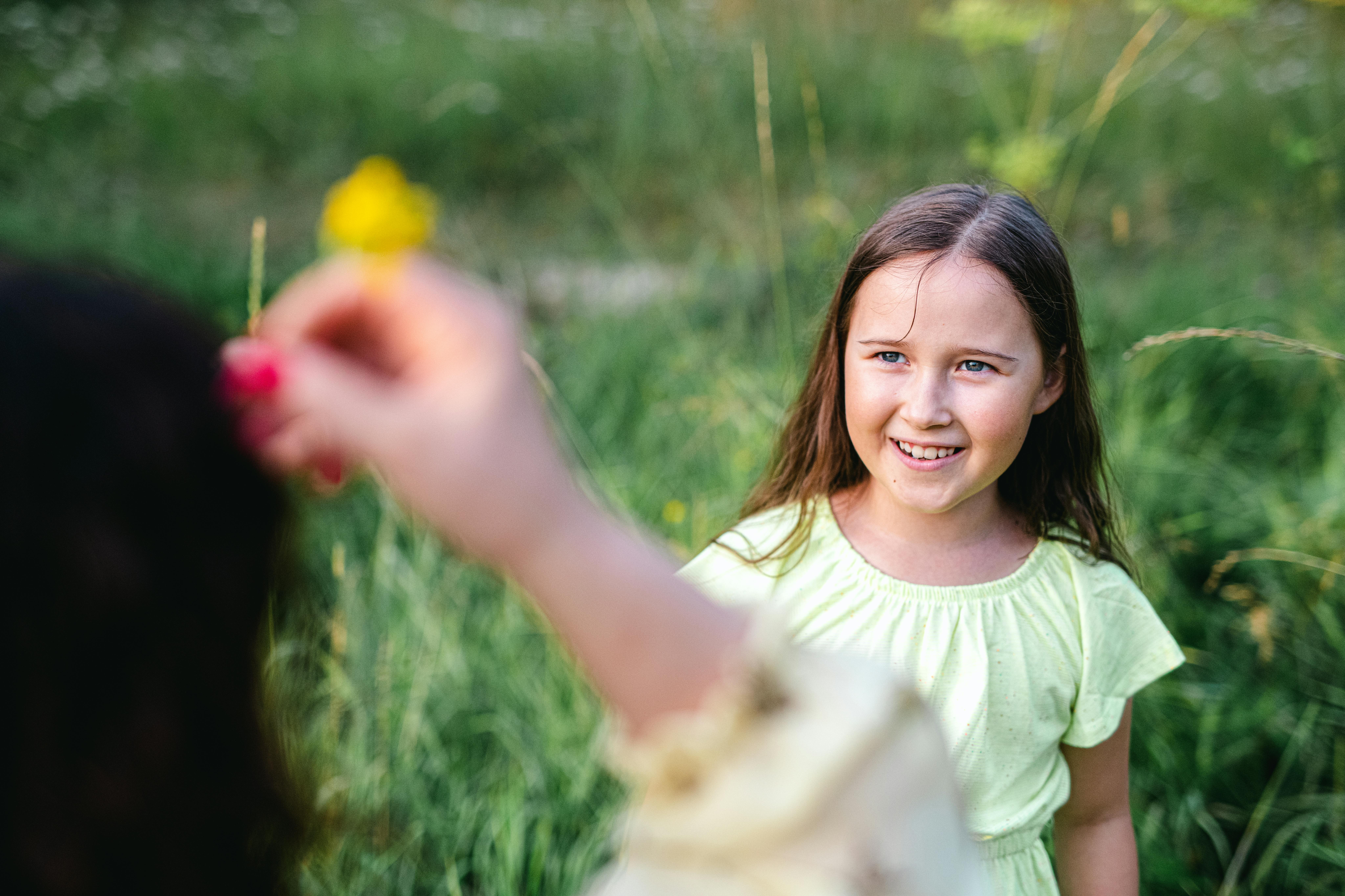 Smiling Girl Looking at Hand Holding Flower · Free Stock Photo