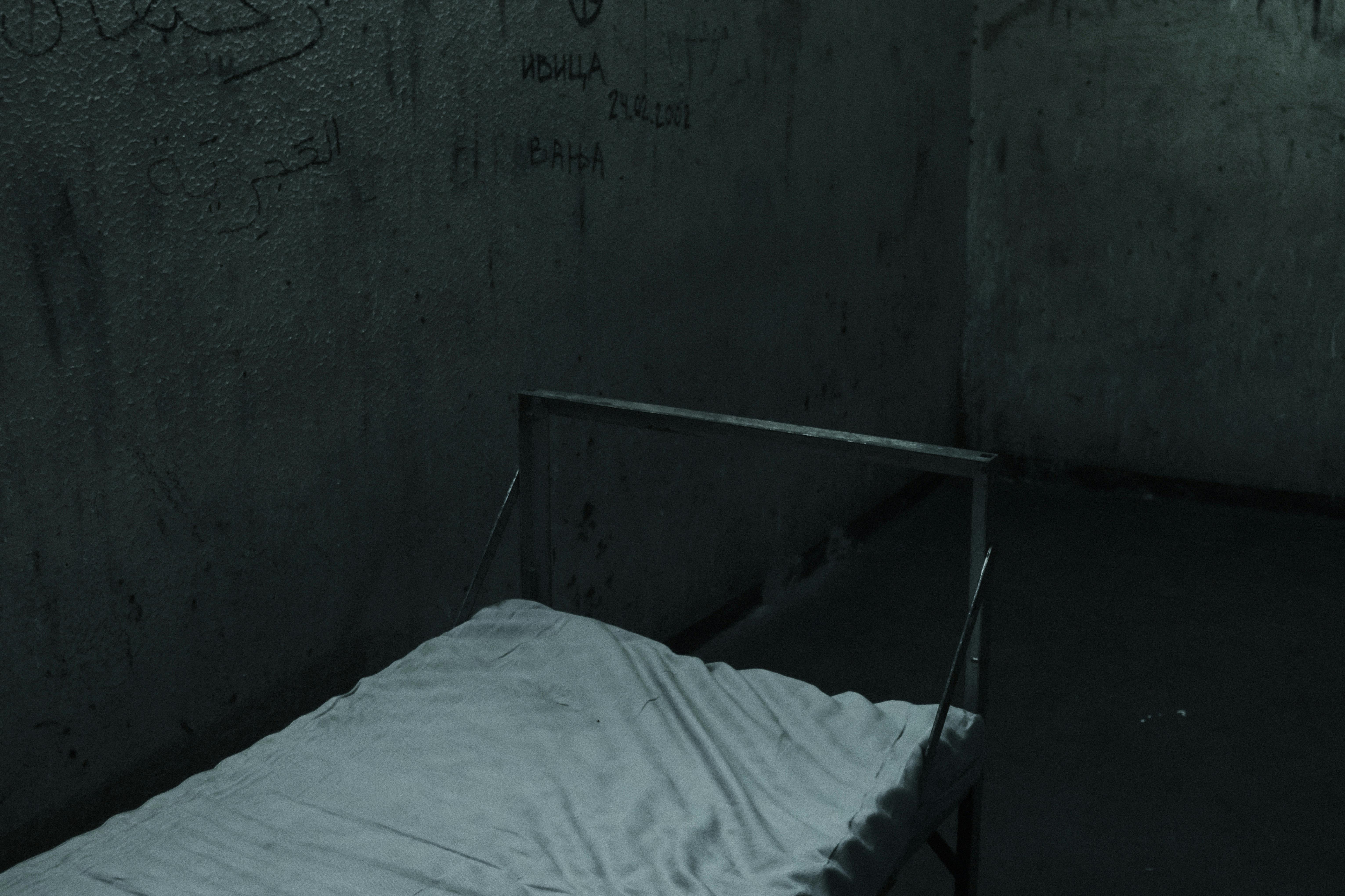 Metal Bed in a Concrete Prison Cell with Names Scribbled on Walls ...