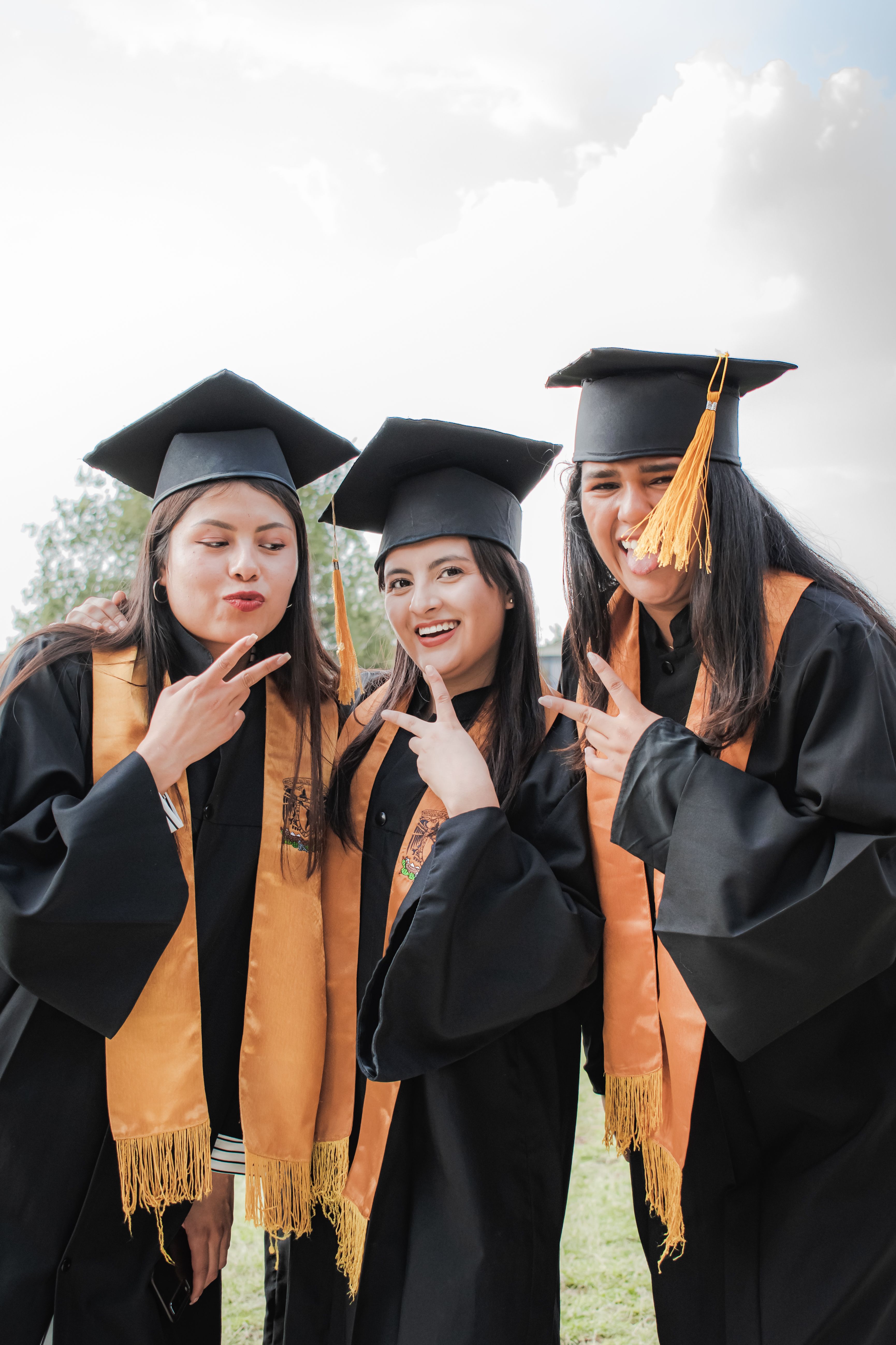 Three Young Women in Graduation Gowns and Caps Posing on a Campus ...