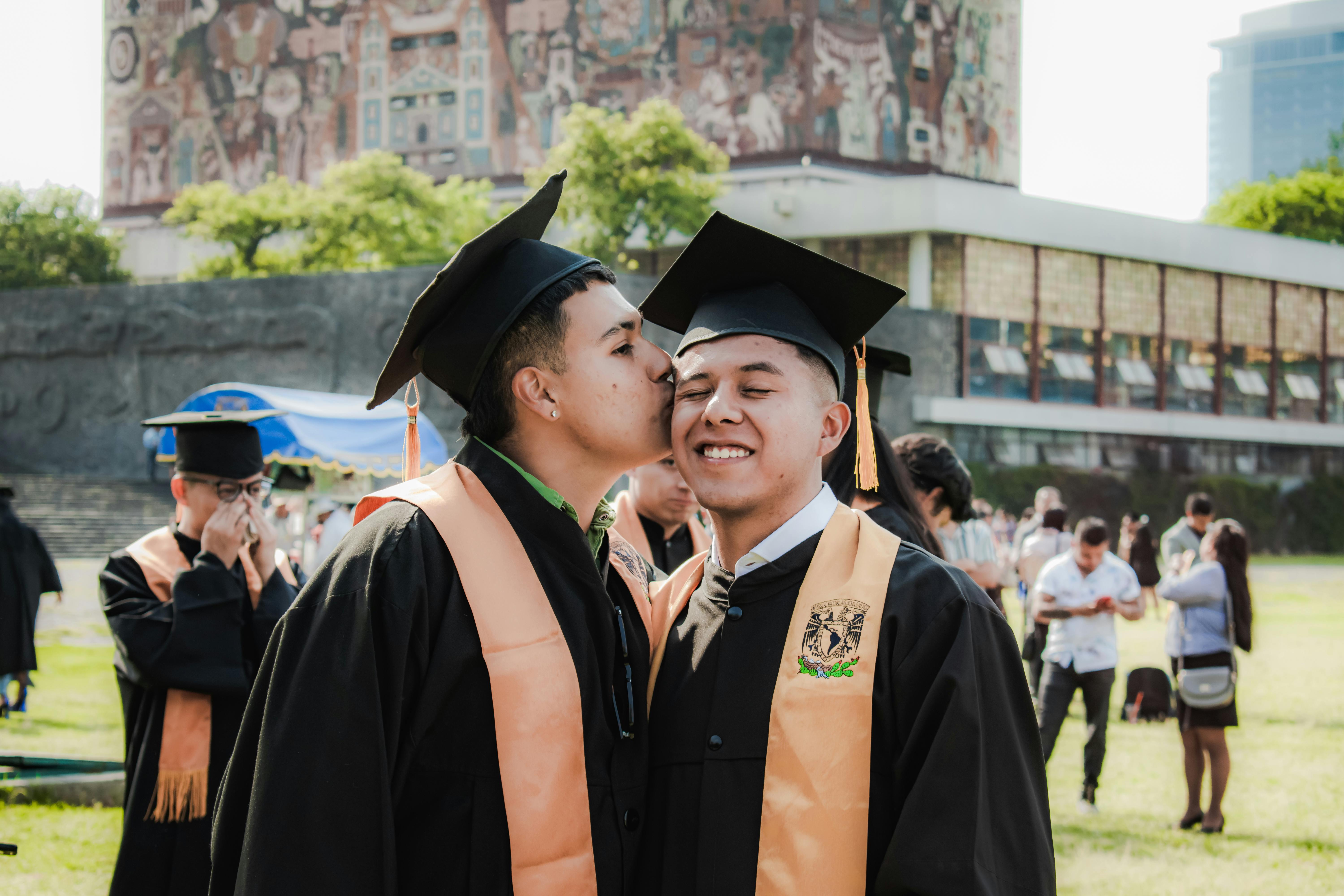 Young Alumnus Kissing his Friend at a University Graduation Ceremony ...