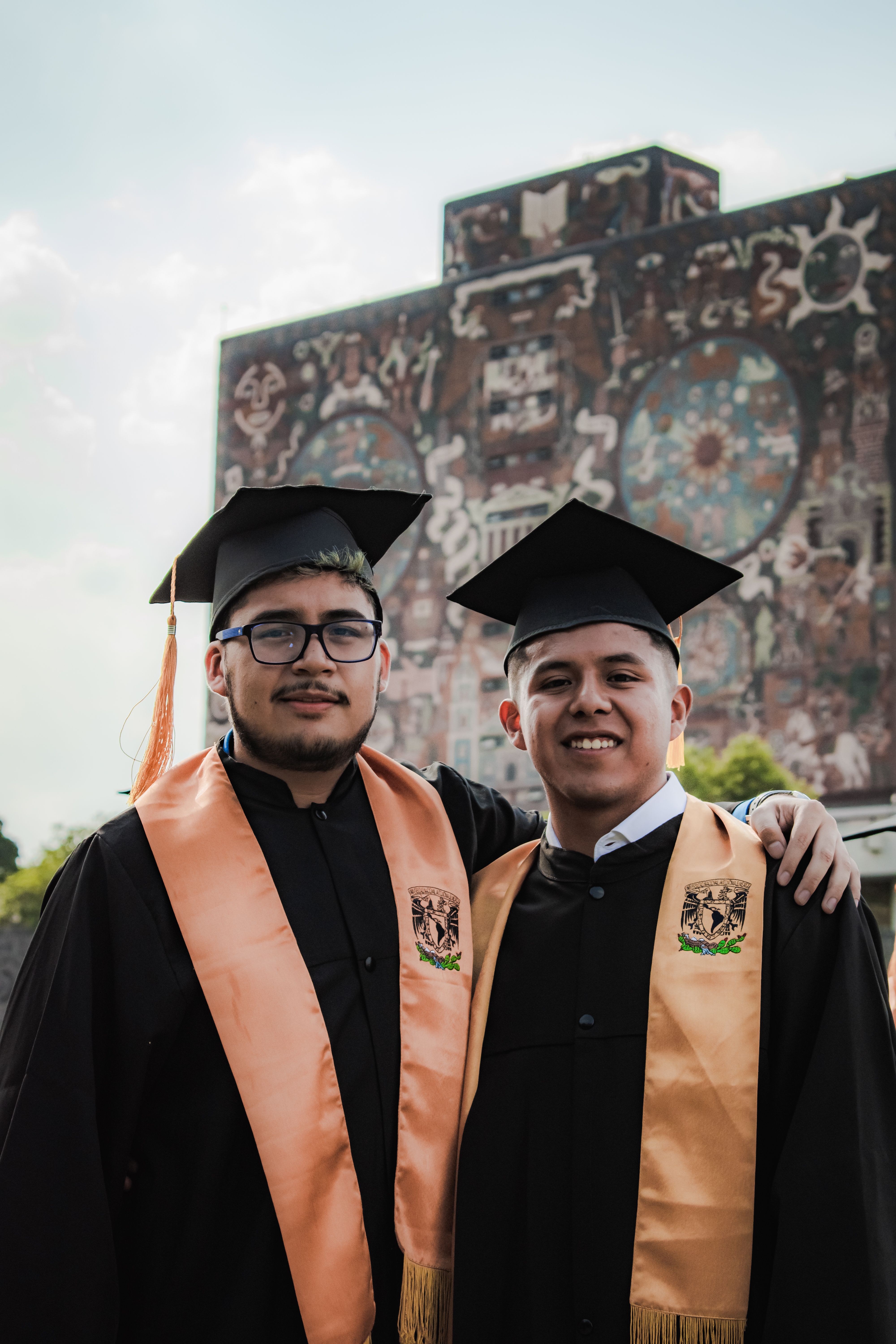 Two Men In Black Graduation Gowns and Caps Standing in front of the ...
