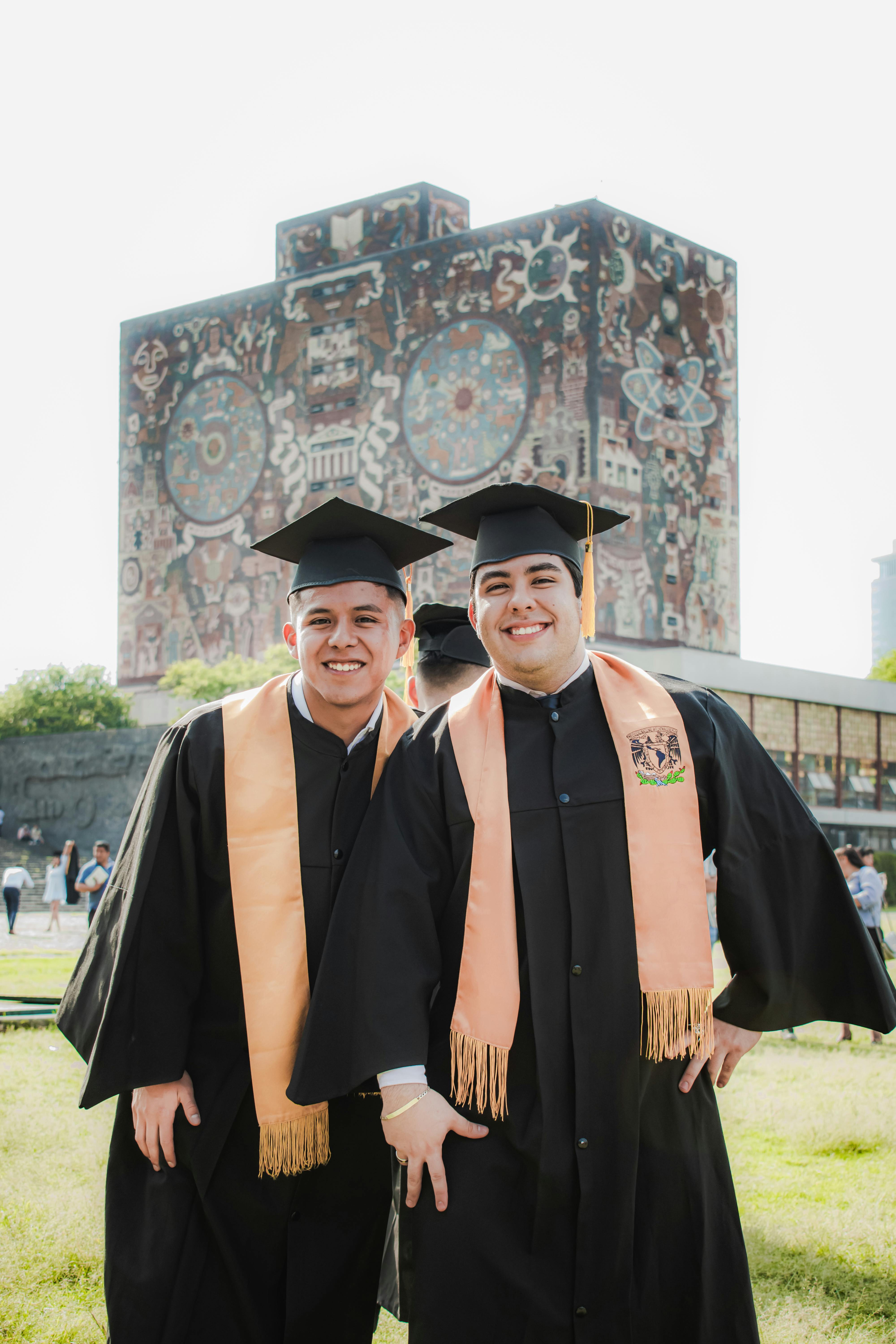 Two Young Men in Black Caps and Gowns Posing at a University Graduation ...