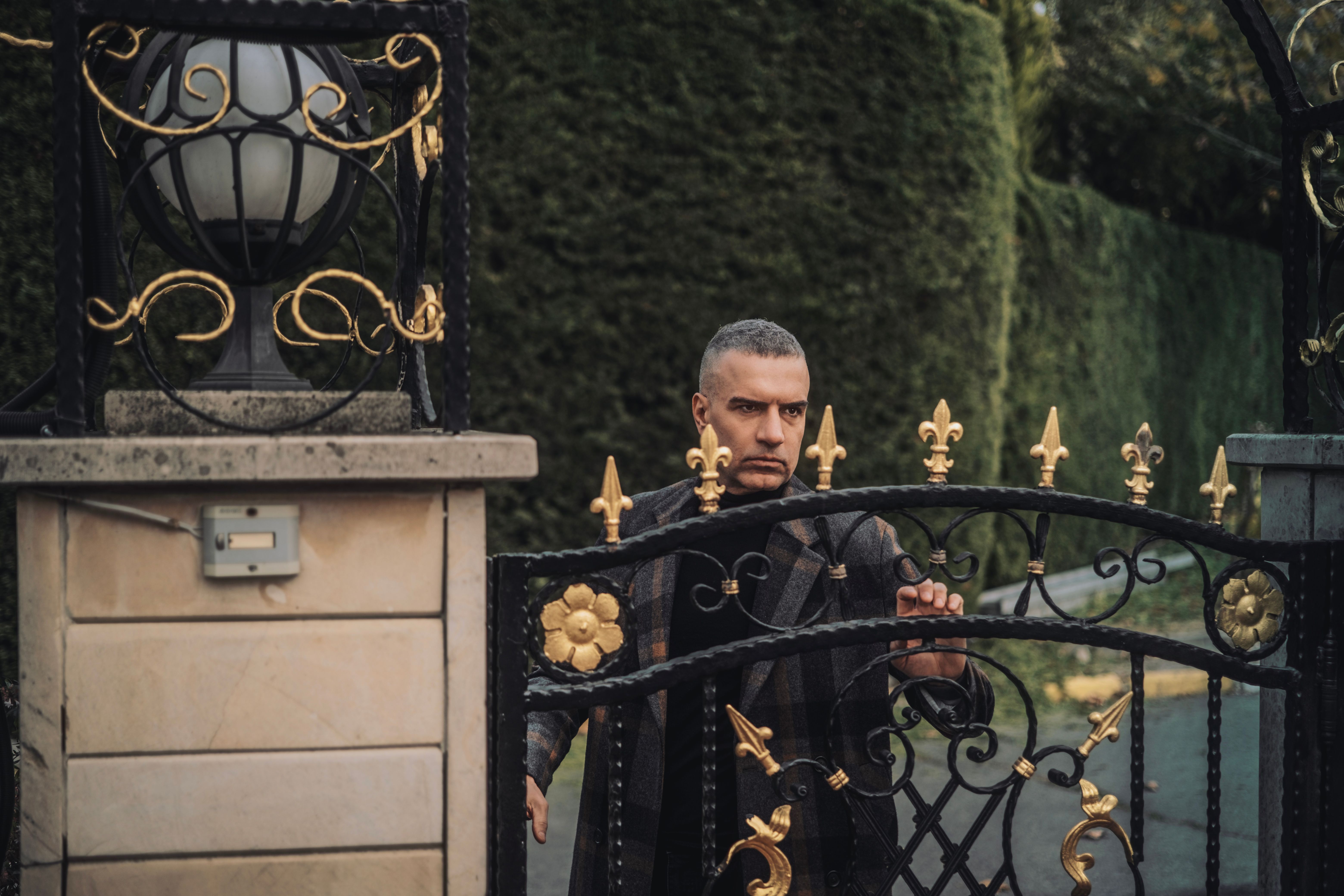 Man in a Coat Standing behind a Gate · Free Stock Photo