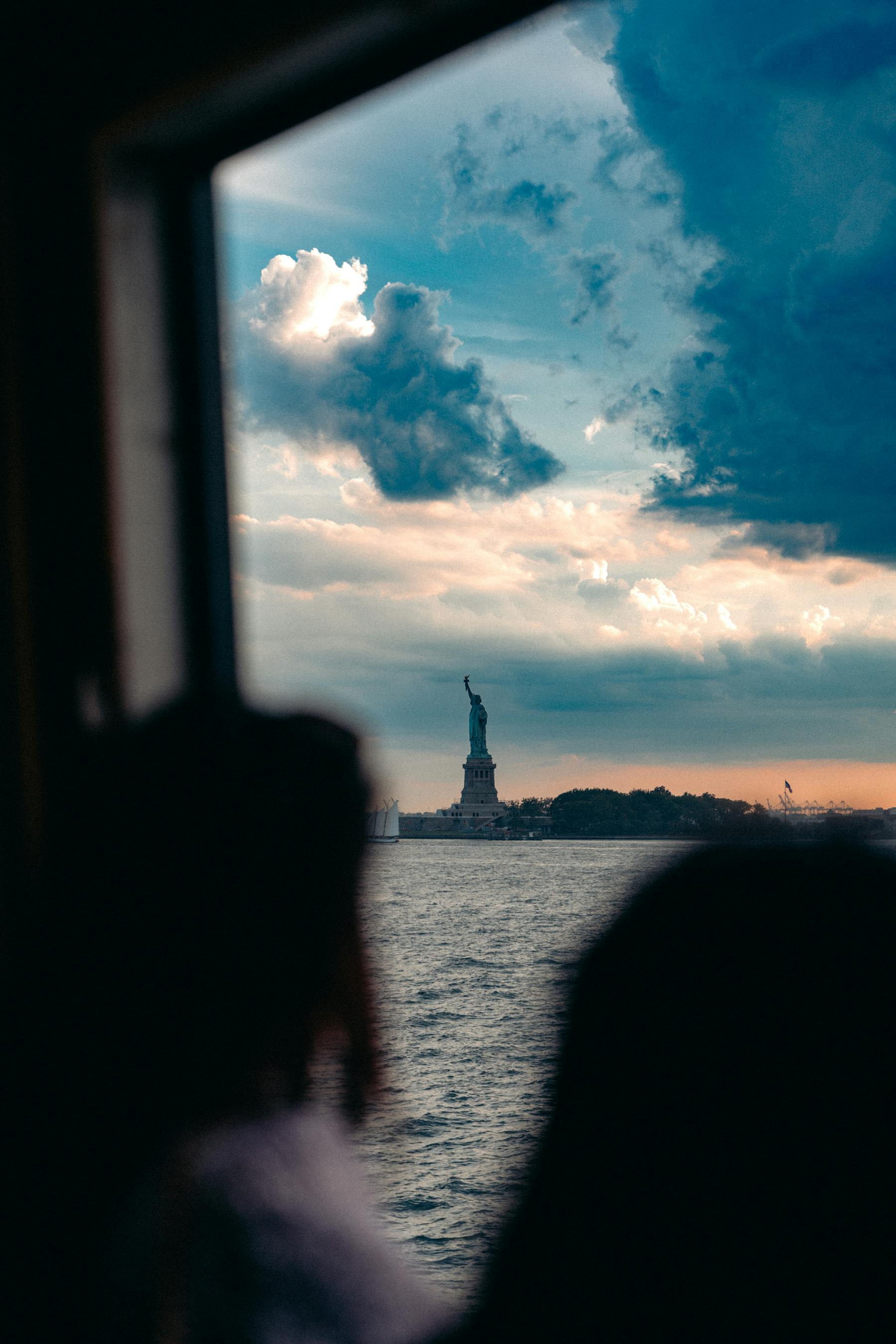 People Heads near Window with Statue of Liberty behind at Sunset · Free ...