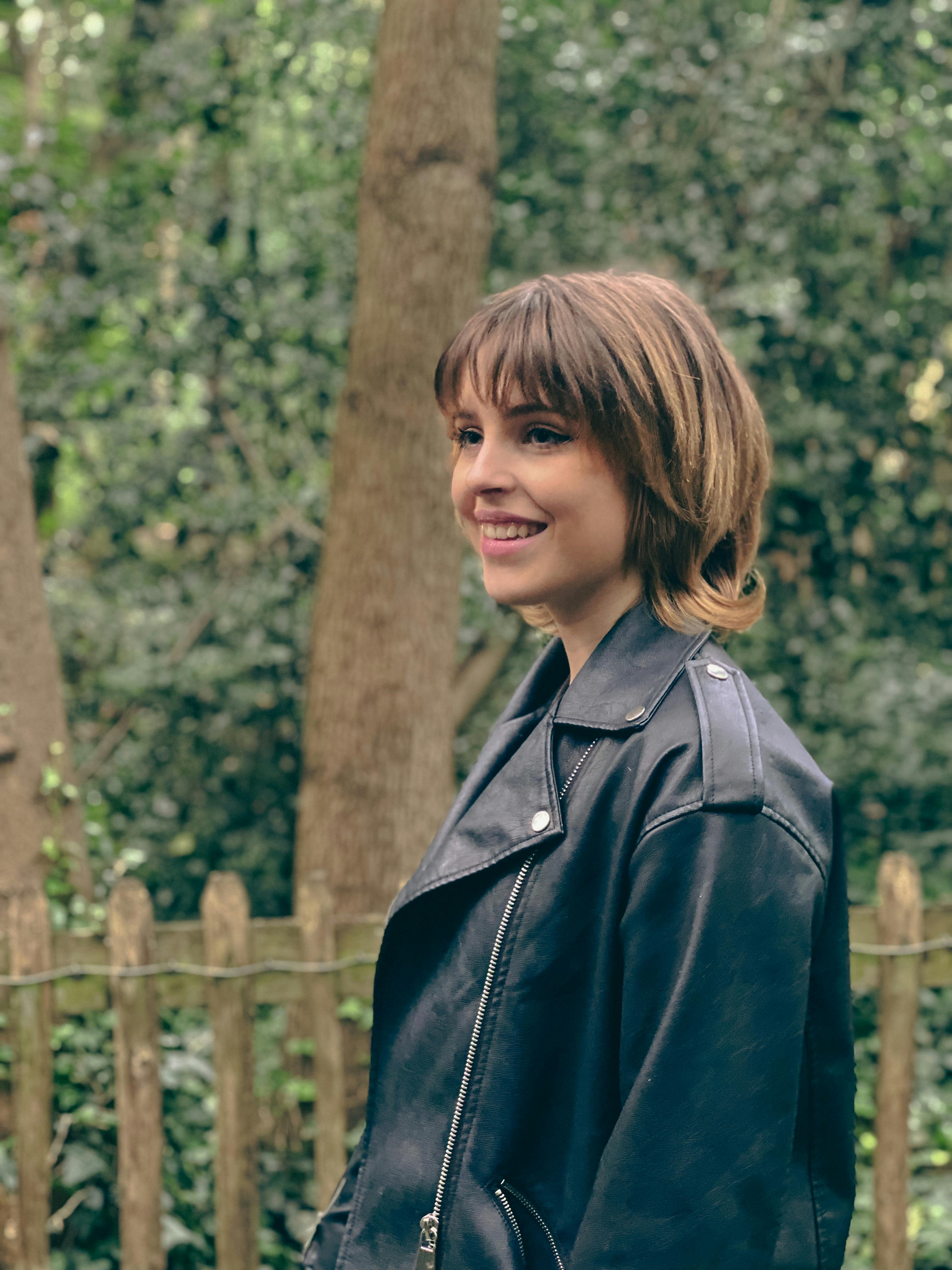 Smiling Woman in Leather Jacket in Park · Free Stock Photo