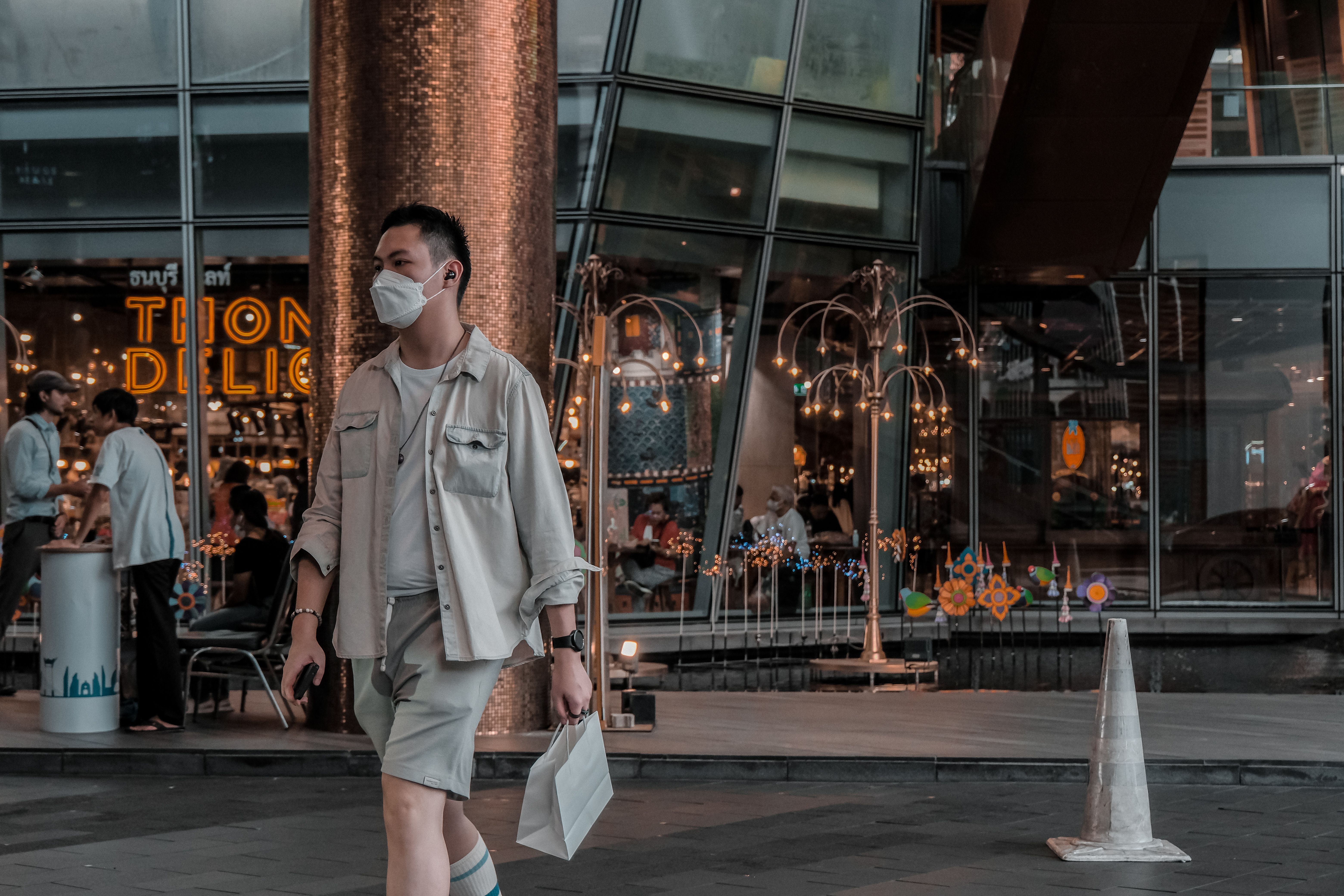 A man wearing a face mask walks through a shopping mall · Free Stock Photo
