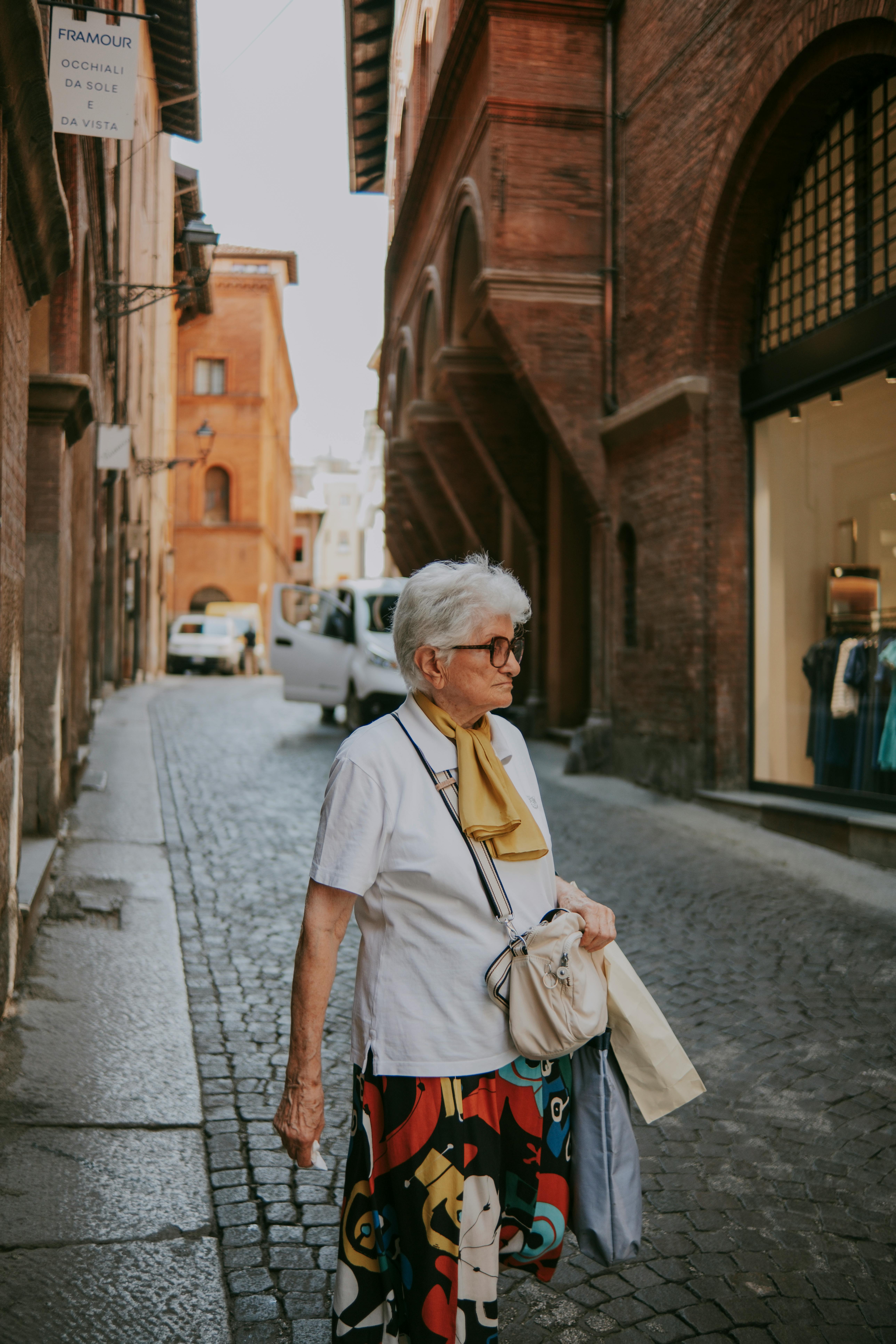 An Elderly Lady Walking Through an Old Town · Free Stock Photo