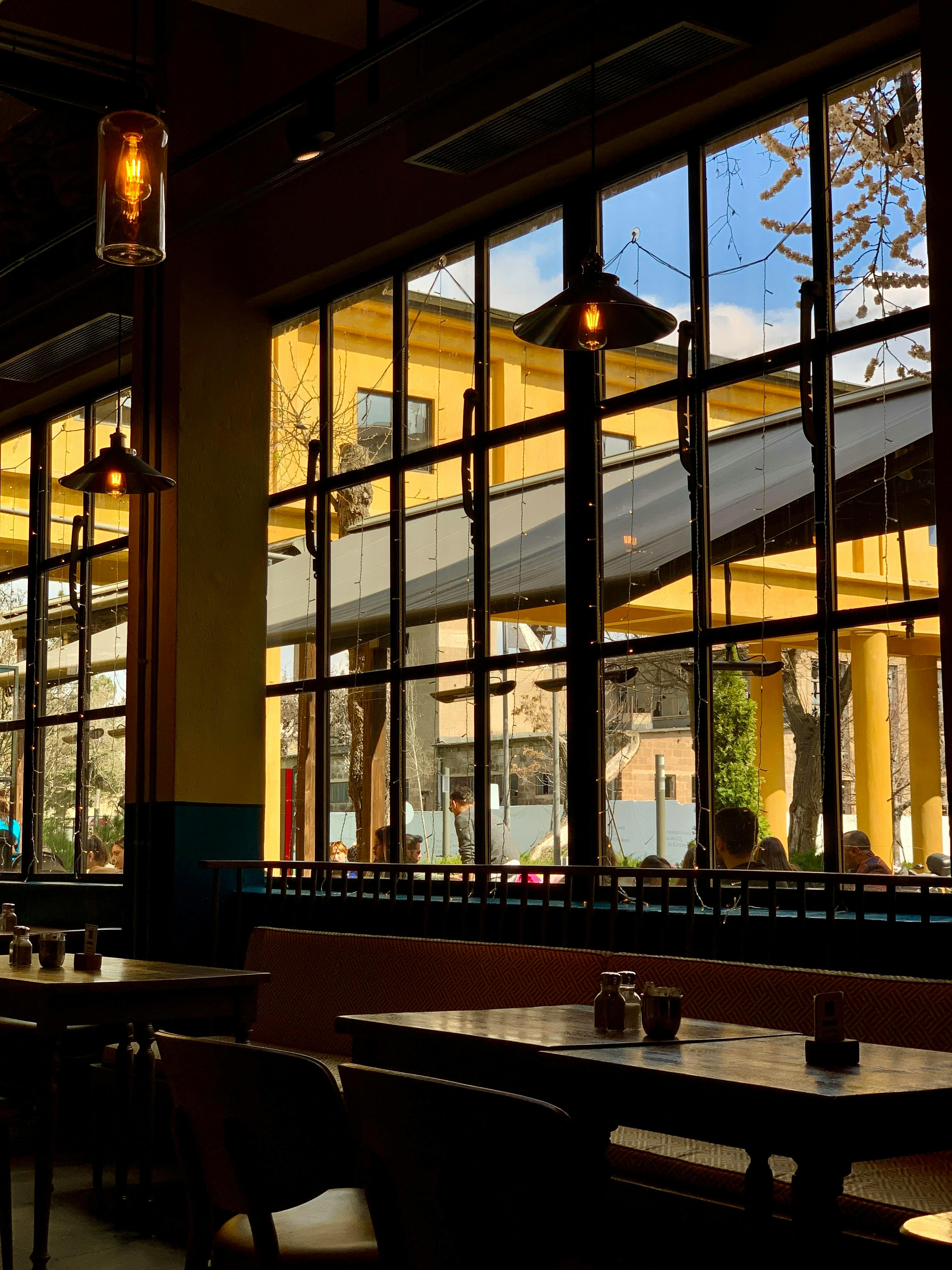 Cozy Cafe with Wooden Furniture and Large Windows · Free Stock Photo