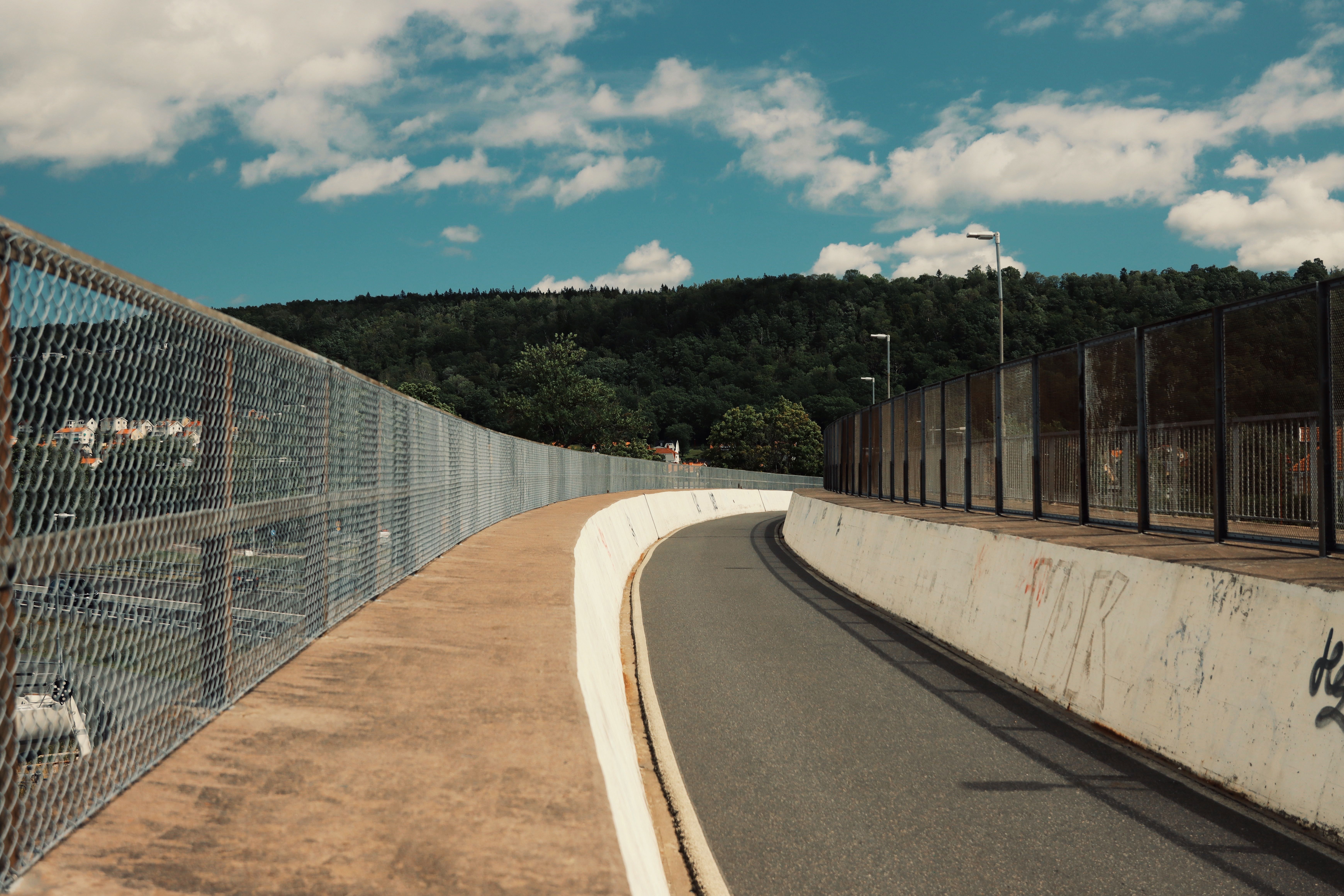 Asphalt Alley with Fence around and Forest behind · Free Stock Photo