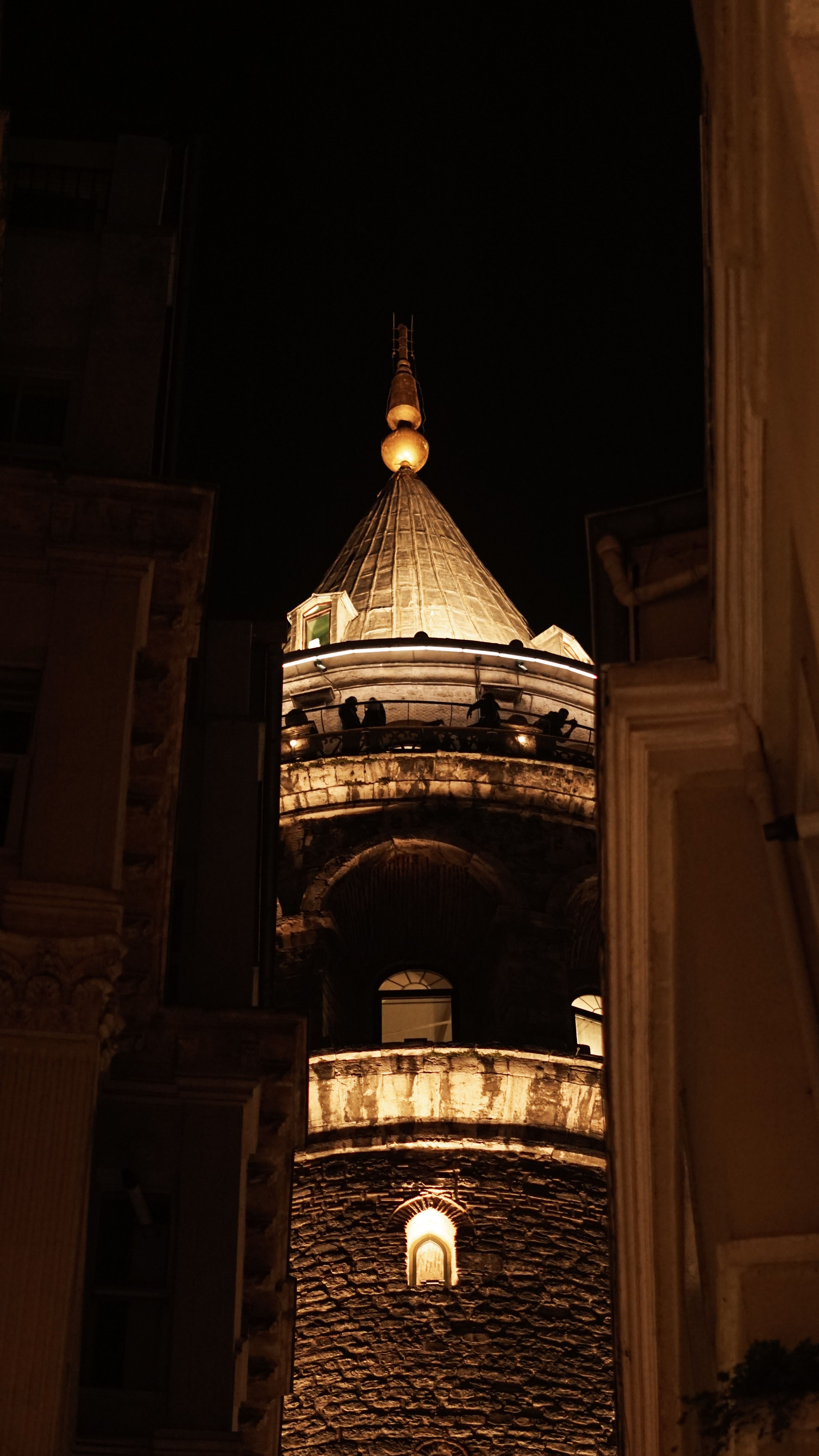 A tower lit up at night with a clock on it · Free Stock Photo