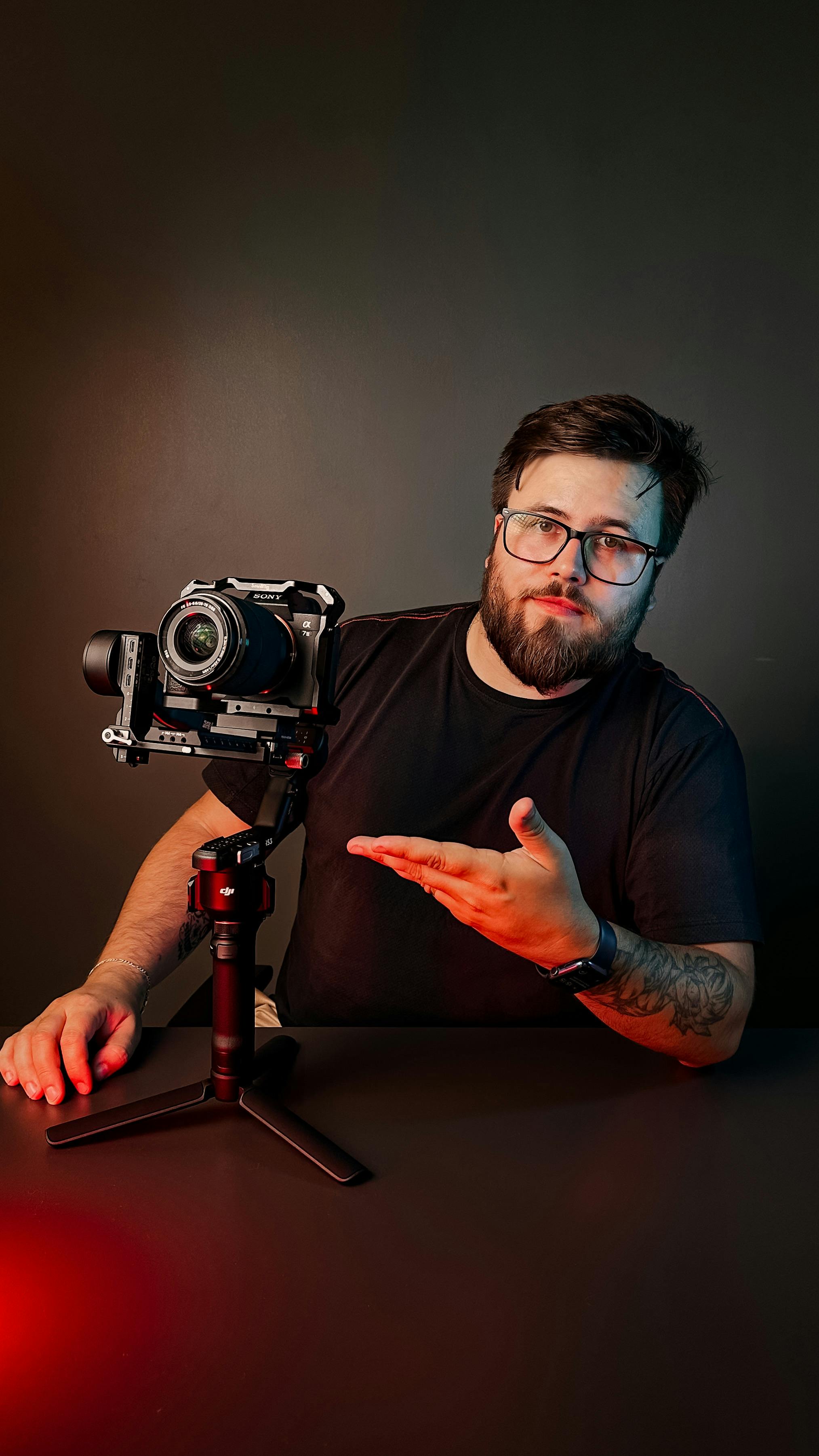 Man Sitting and Showing Camera on Tripod · Free Stock Photo