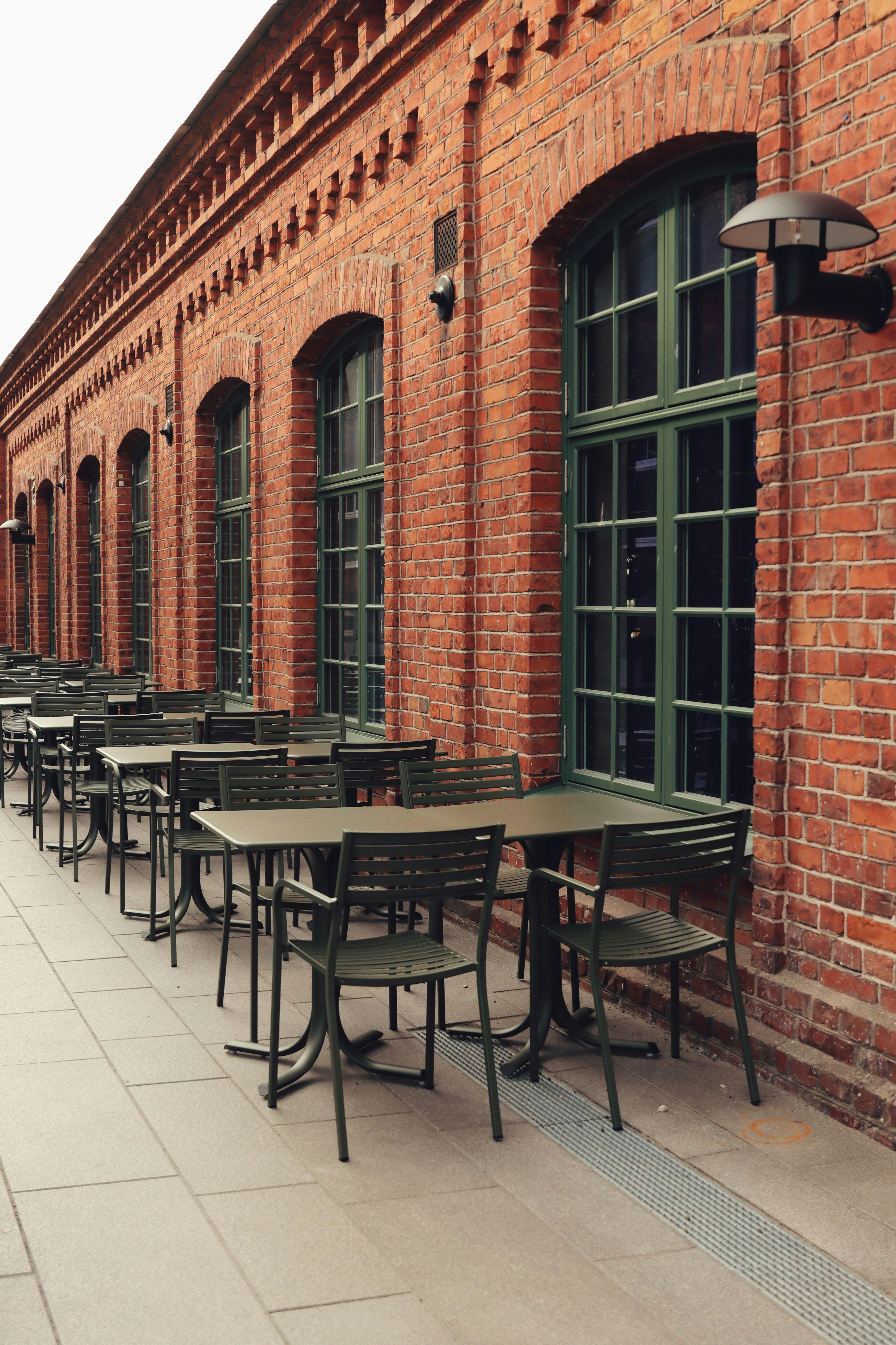 Chairs and Tables by Brick Building of Restaurant · Free Stock Photo