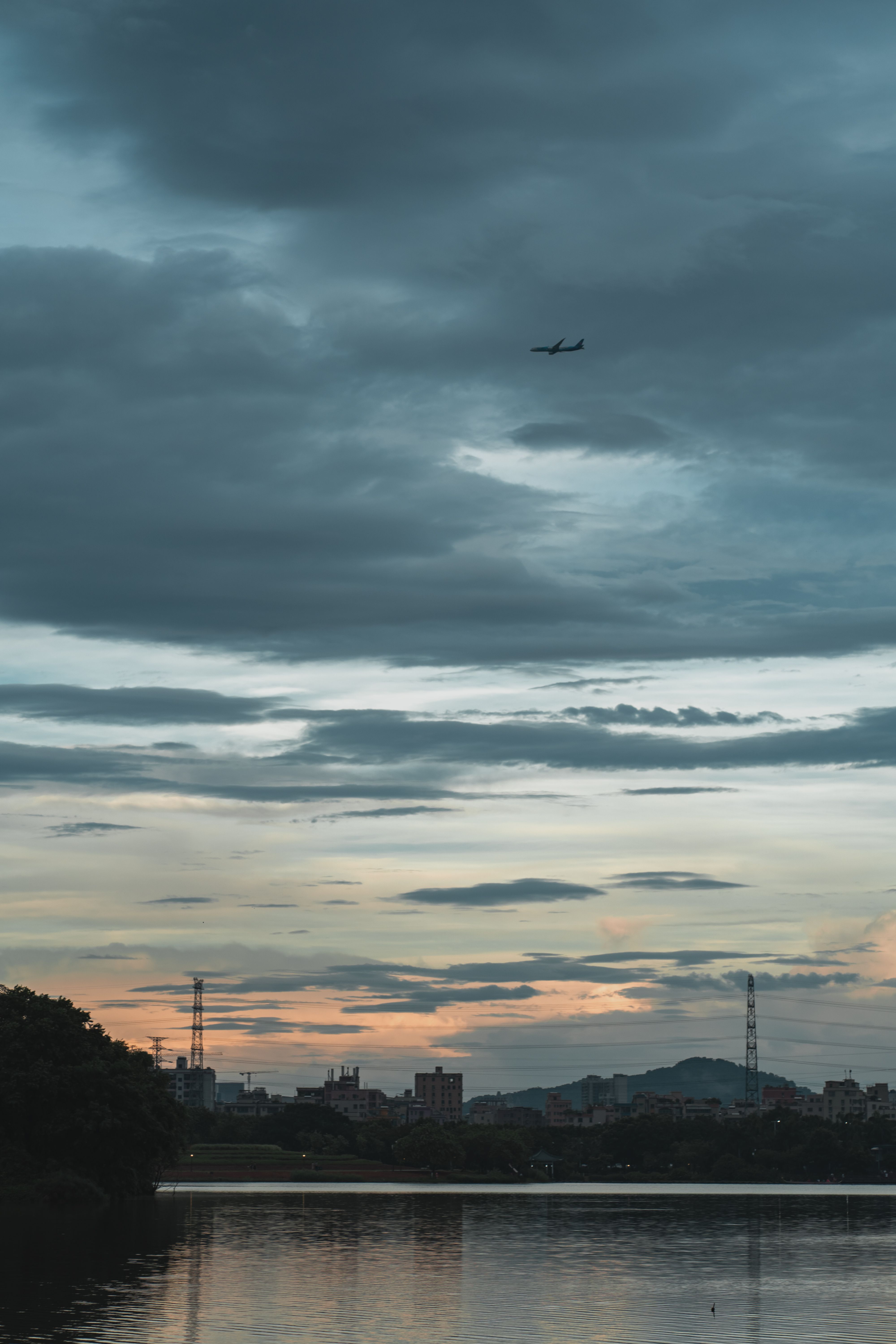 Airplane Flying under Clouds over Town · Free Stock Photo