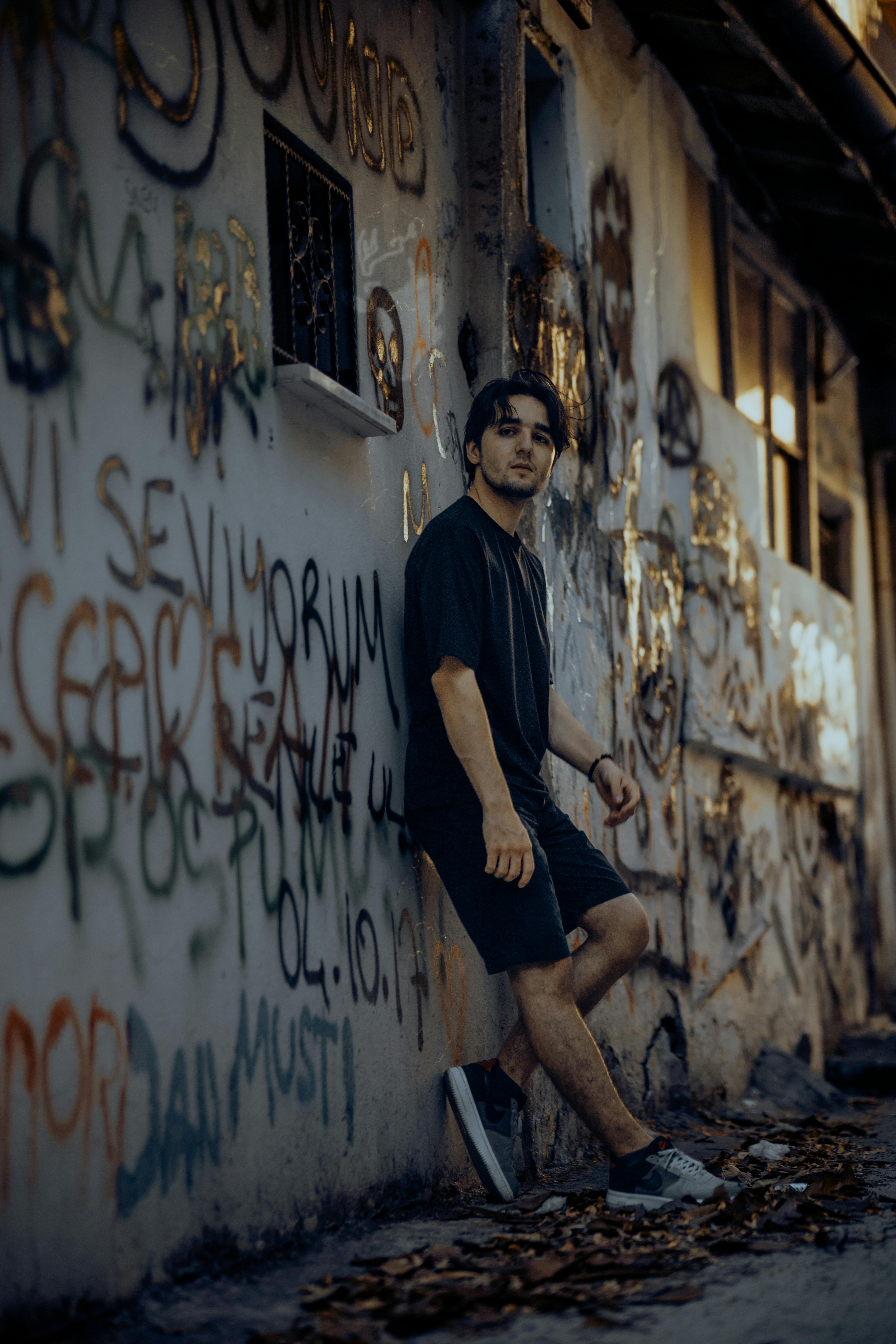 Man in a Sweater Leaning Against a Wall Covered with Graffiti · Free ...
