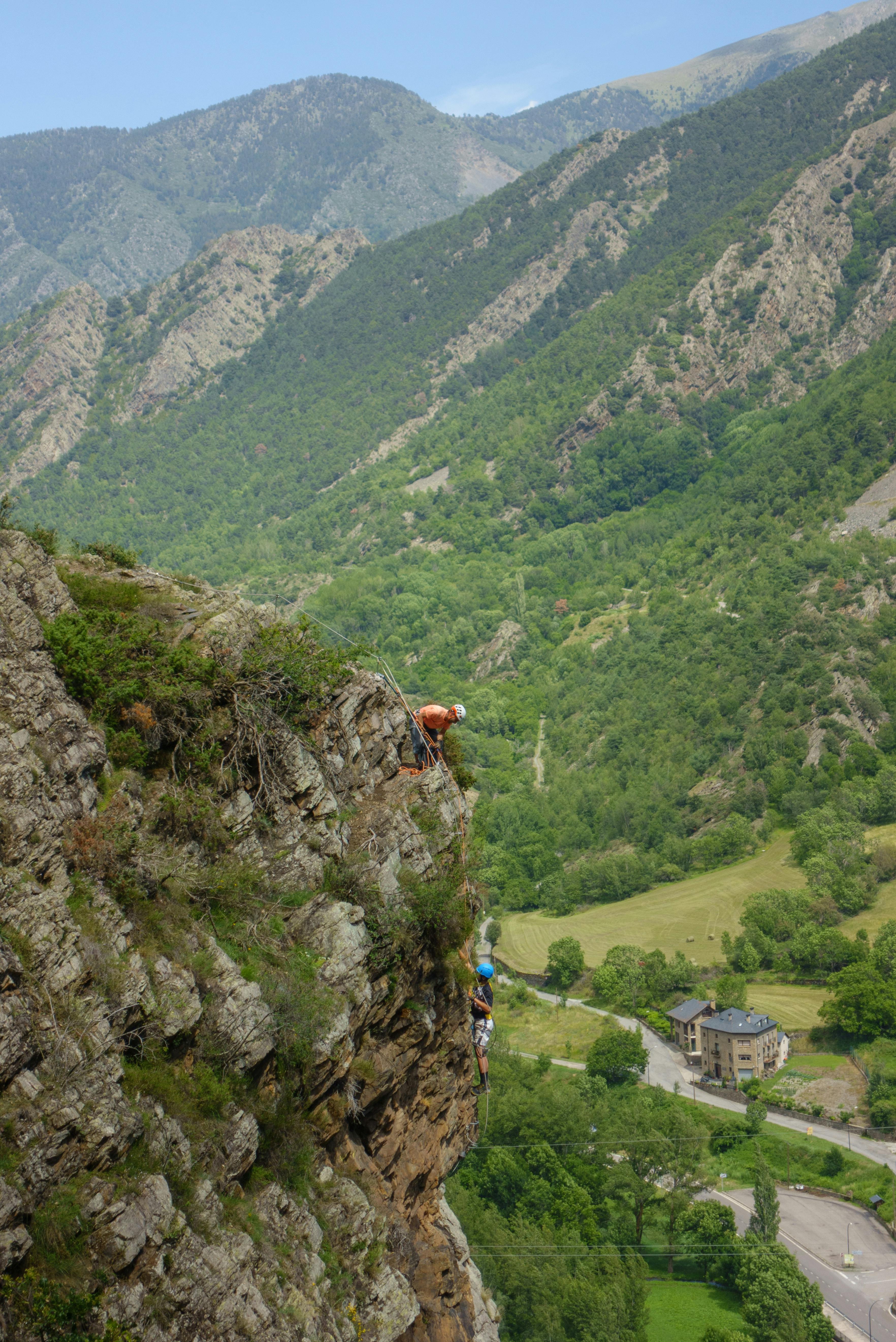 People Climbing on a Steep Cliff over a Mountain Valley · Free Stock Photo