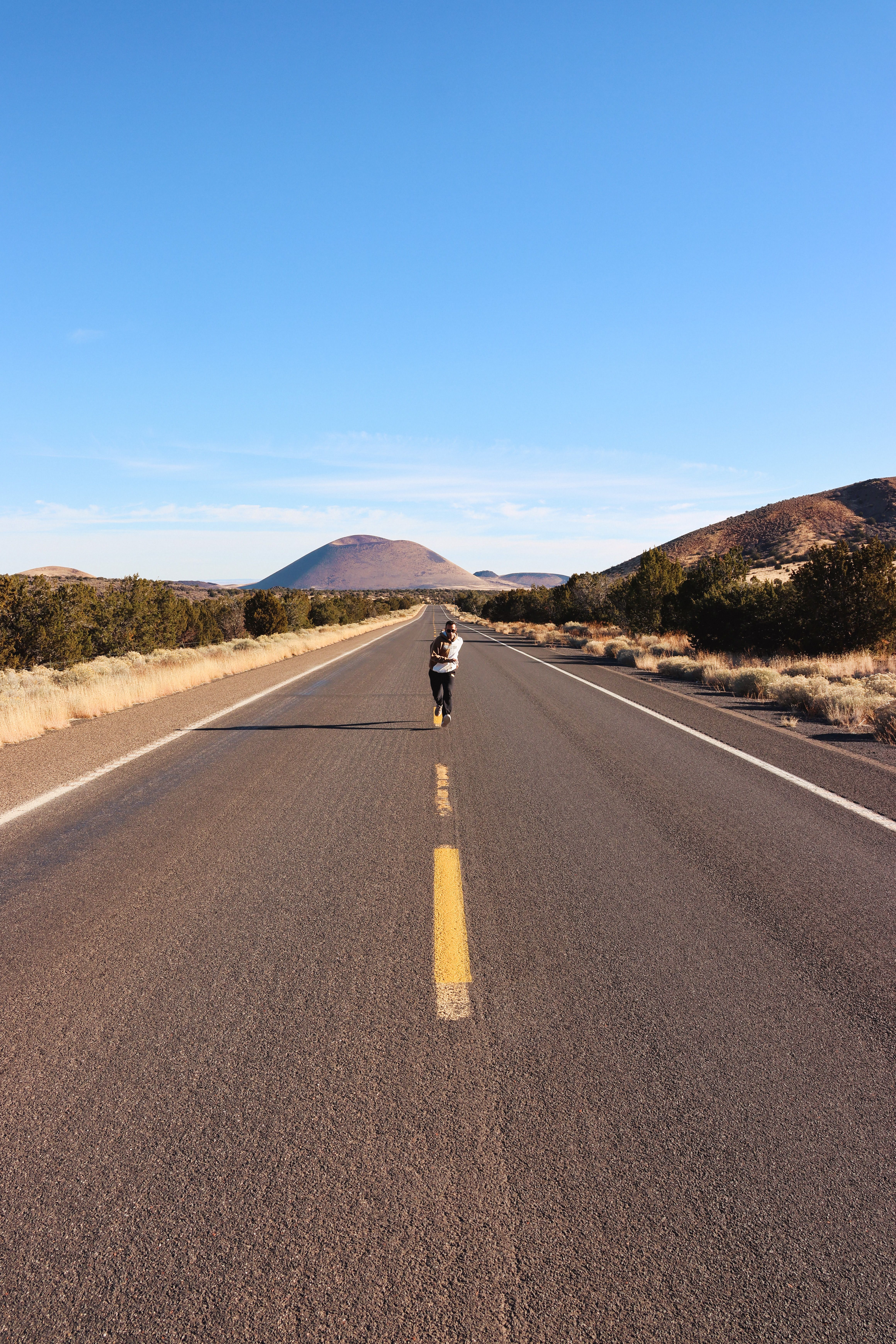 Man Running on Empty, Sunlit Road · Free Stock Photo