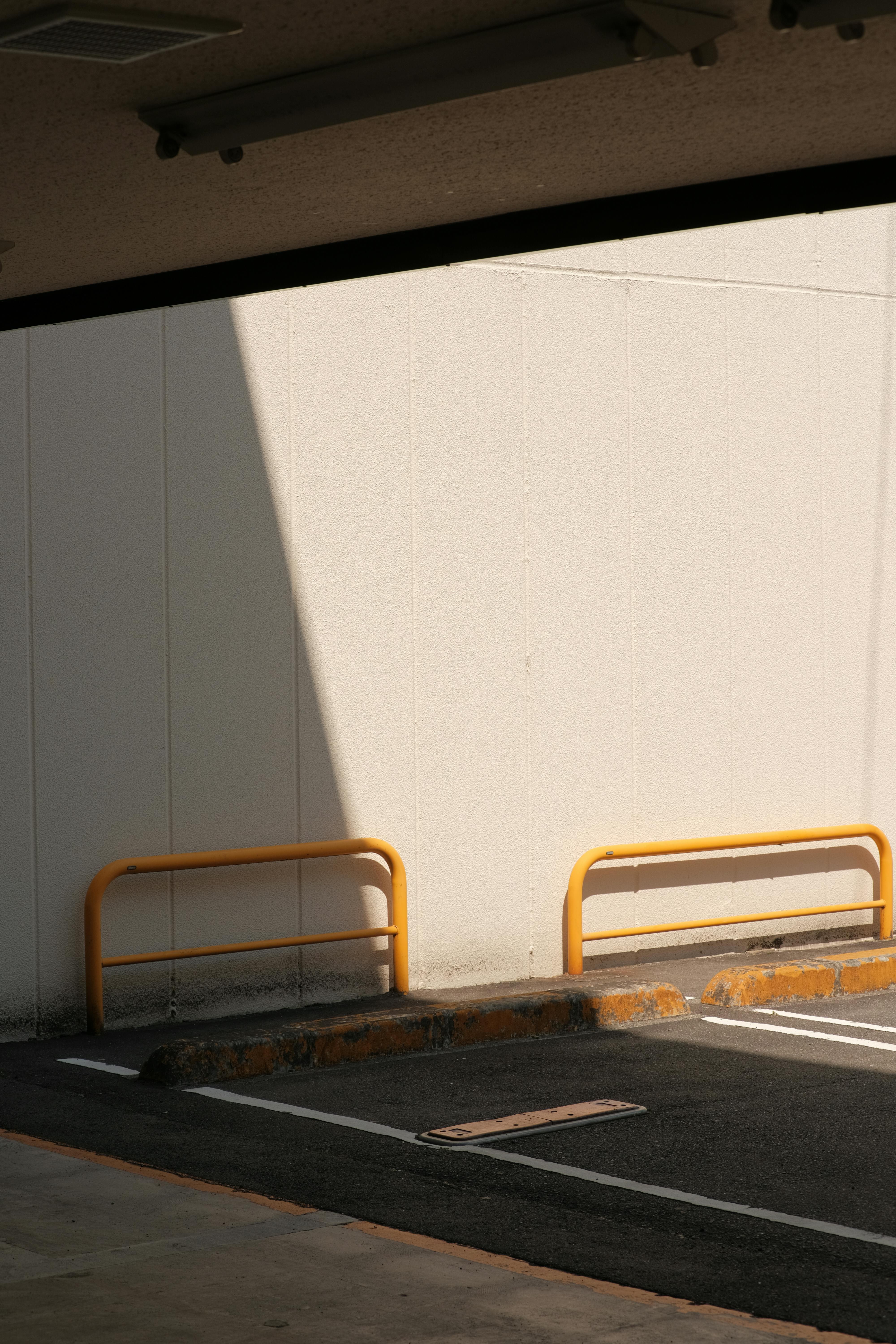 Yellow Safety Barriers by Wall in Parking Lot · Free Stock Photo