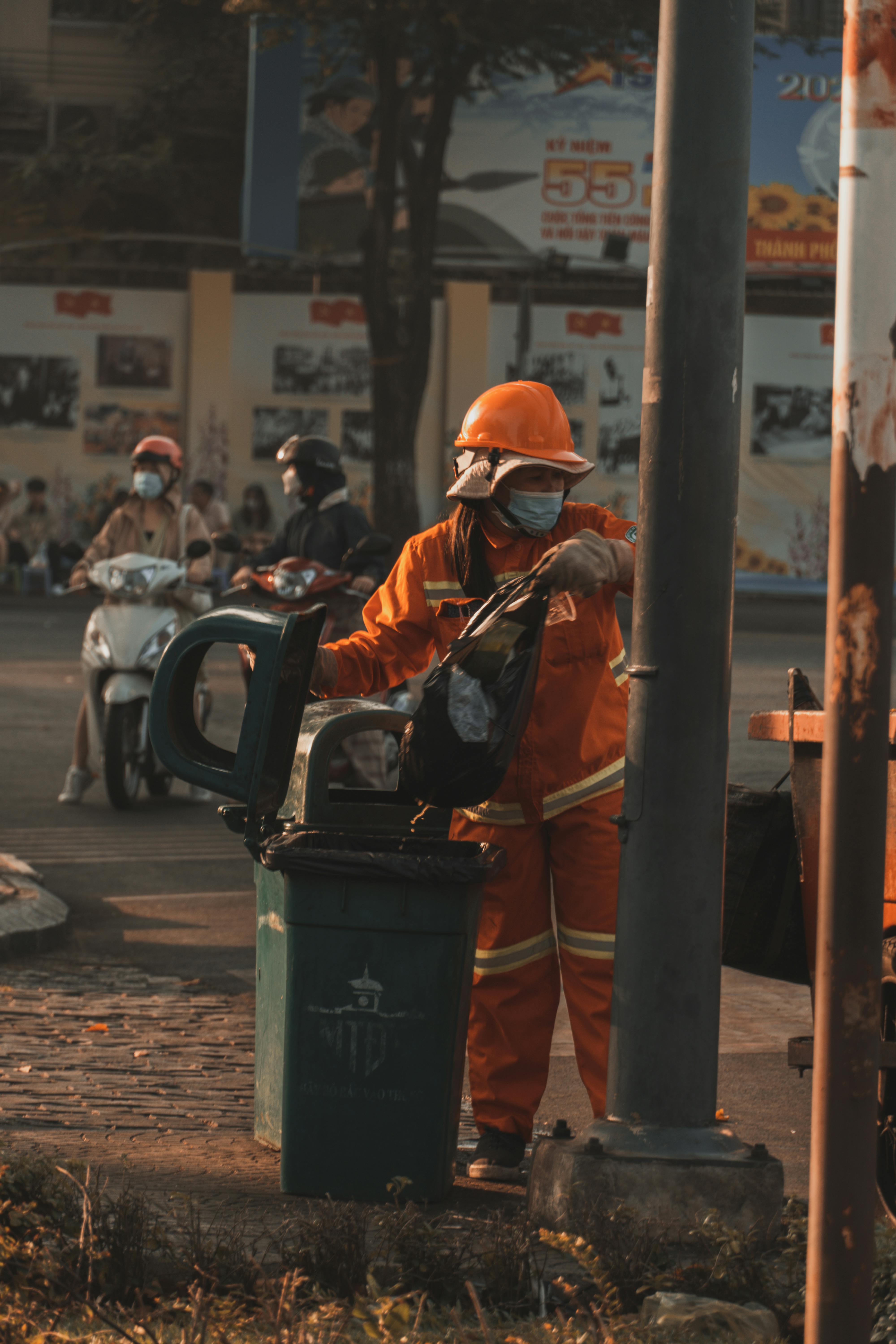 Man in Orange Suit Emptying Trash Can · Free Stock Photo