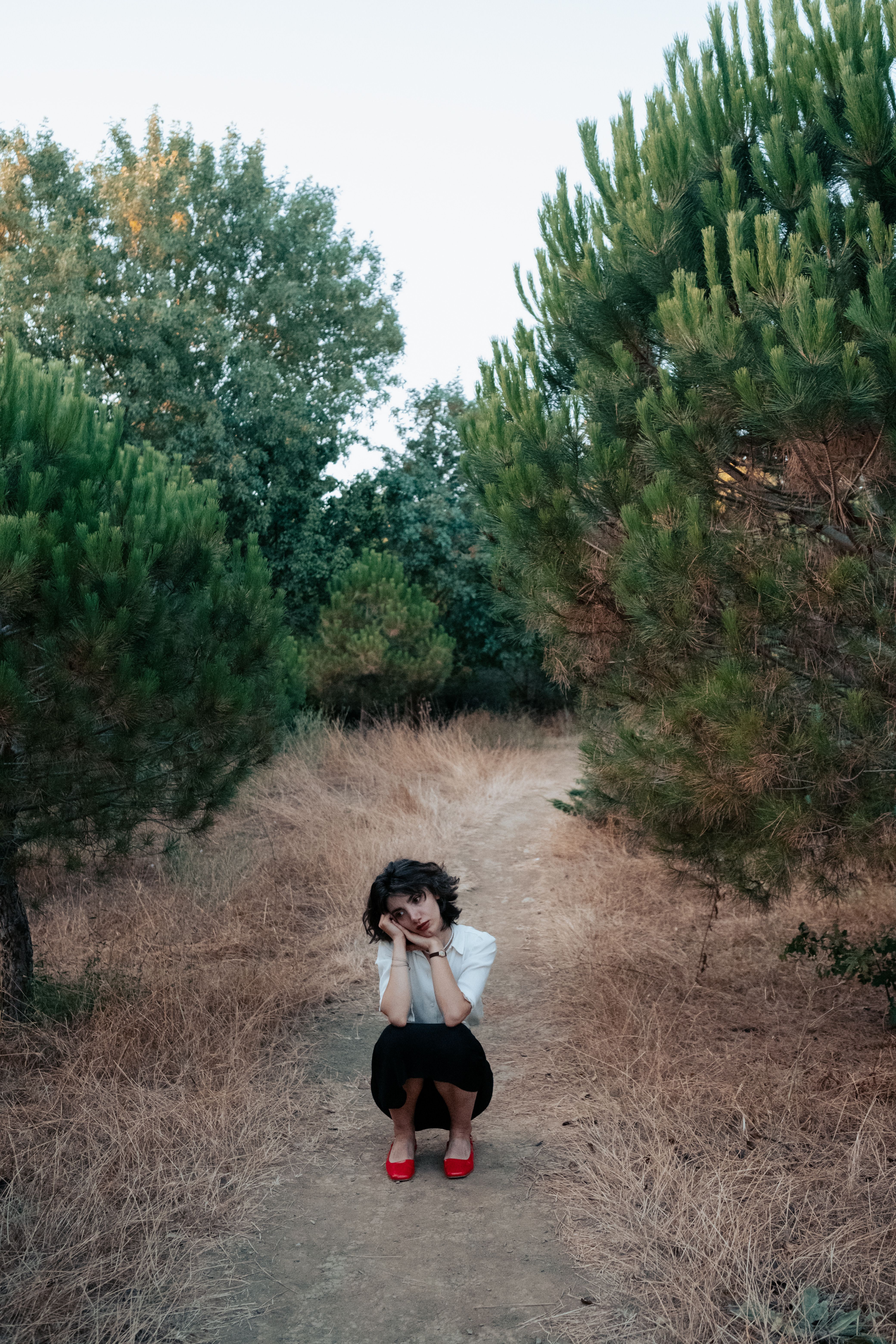 Young Woman Crouching on the Path in the Forest · Free Stock Photo