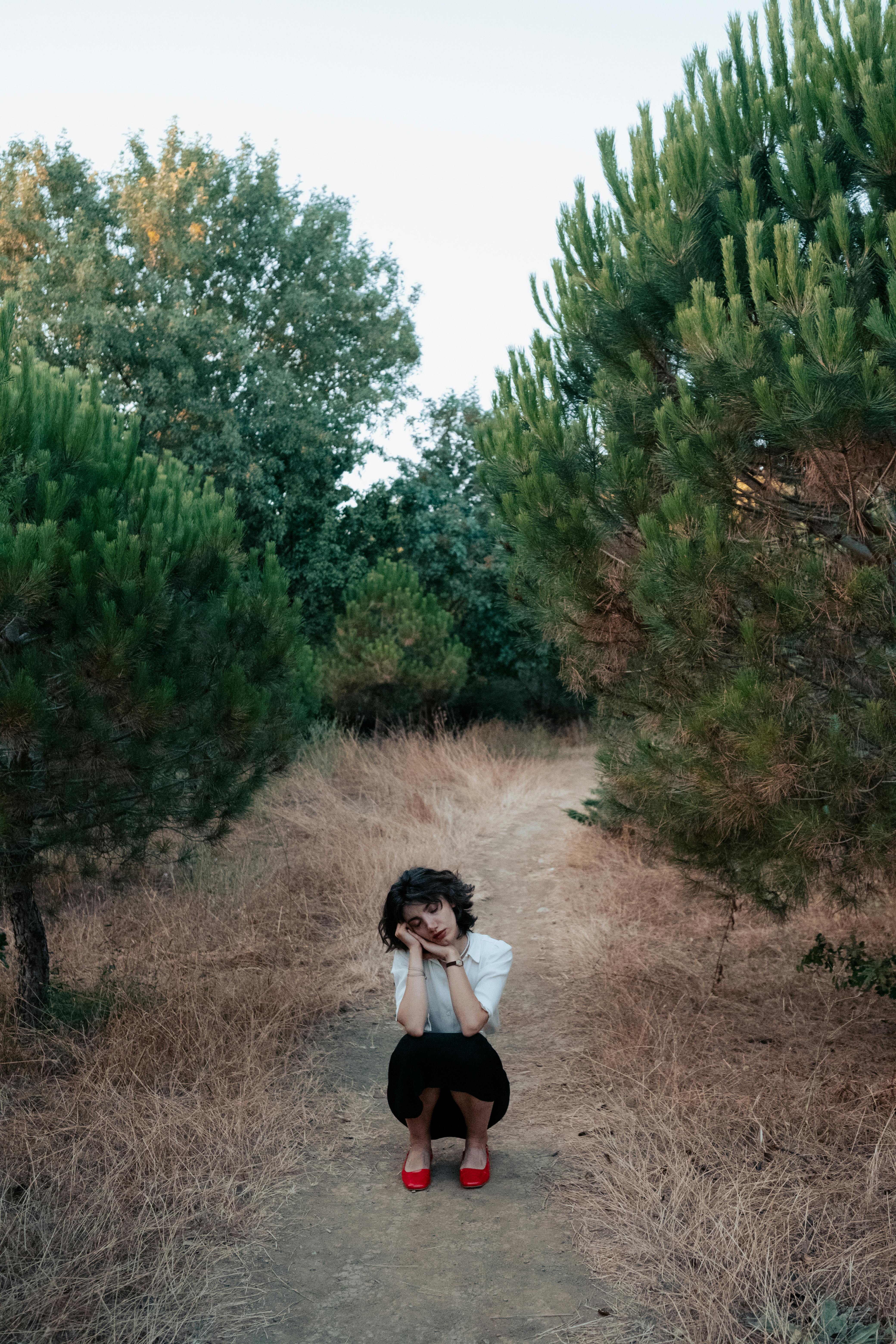 Woman Squatting on Footpath among Trees · Free Stock Photo