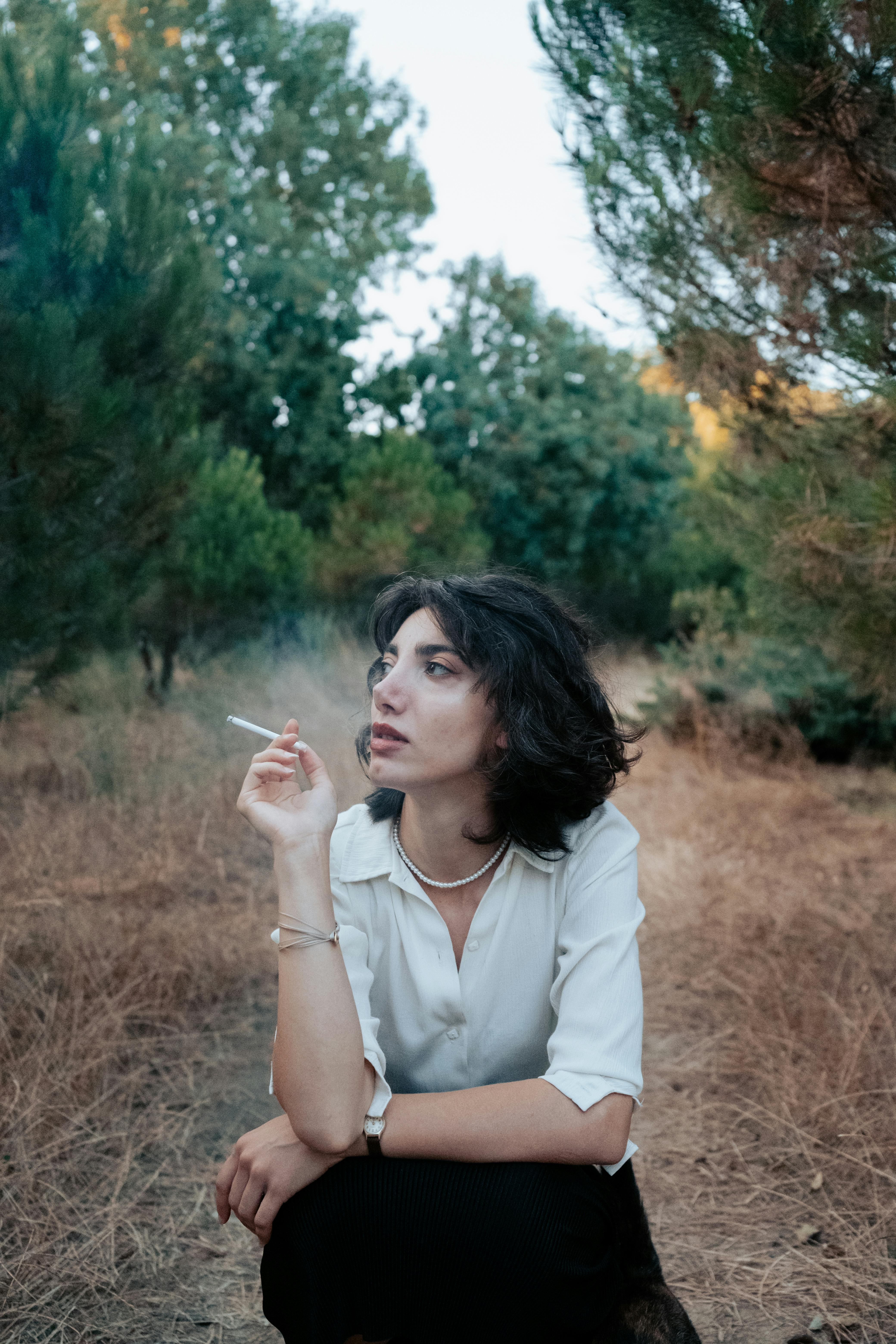 Crouching on Dried Grass Woman Smoking Cigarette · Free Stock Photo