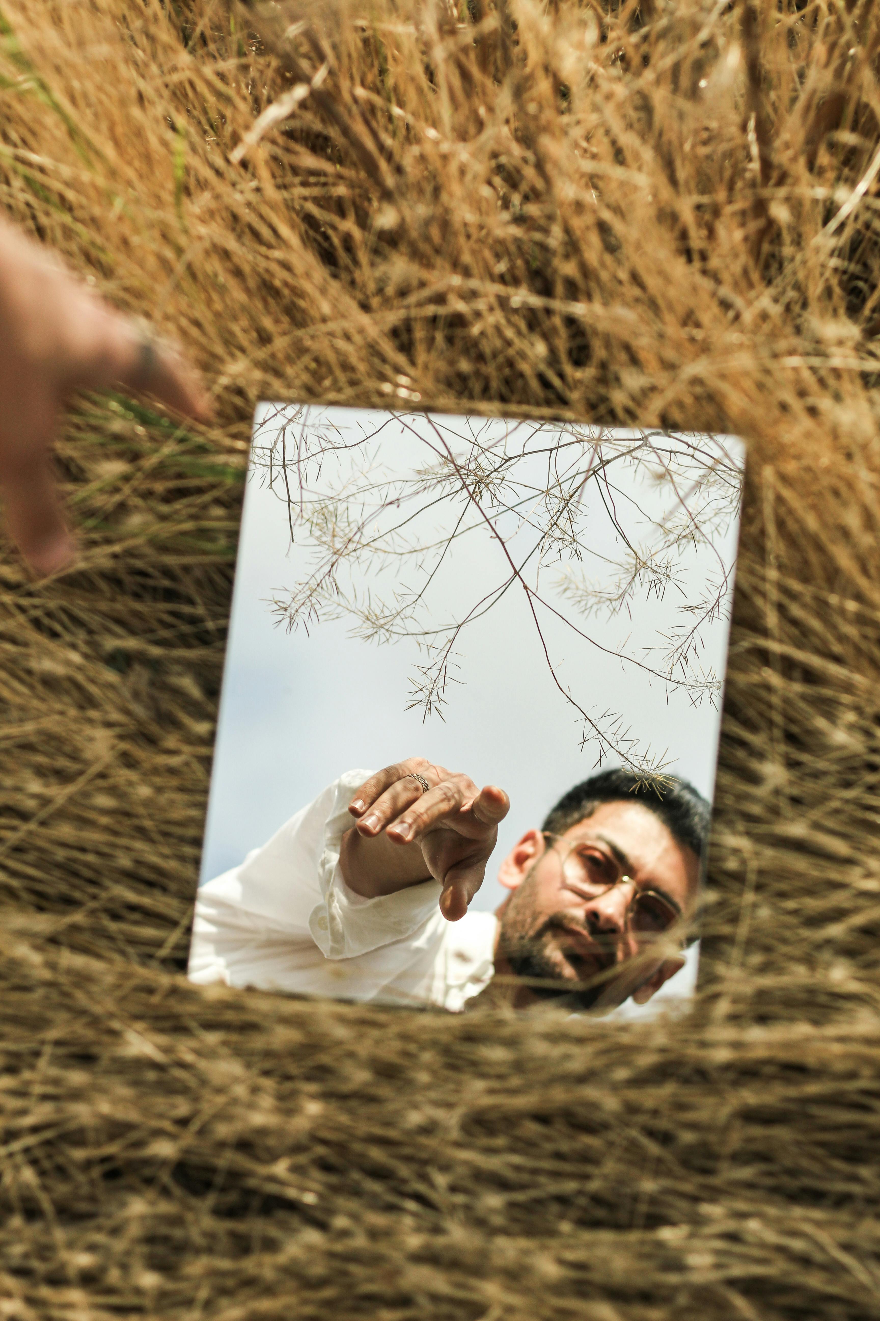 Reflection of a Man Pointing at the Mirror Lying on the Grass · Free ...