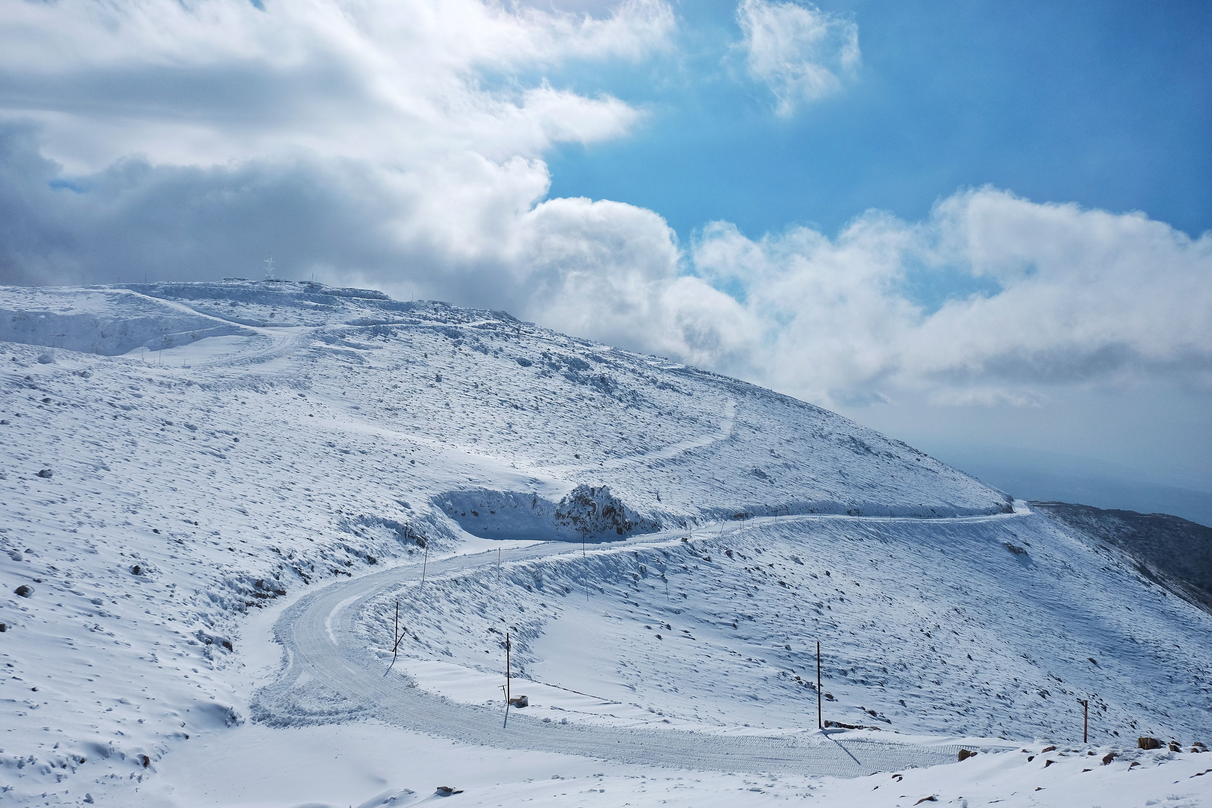 A snowy mountain road with a snow covered hill · Free Stock Photo