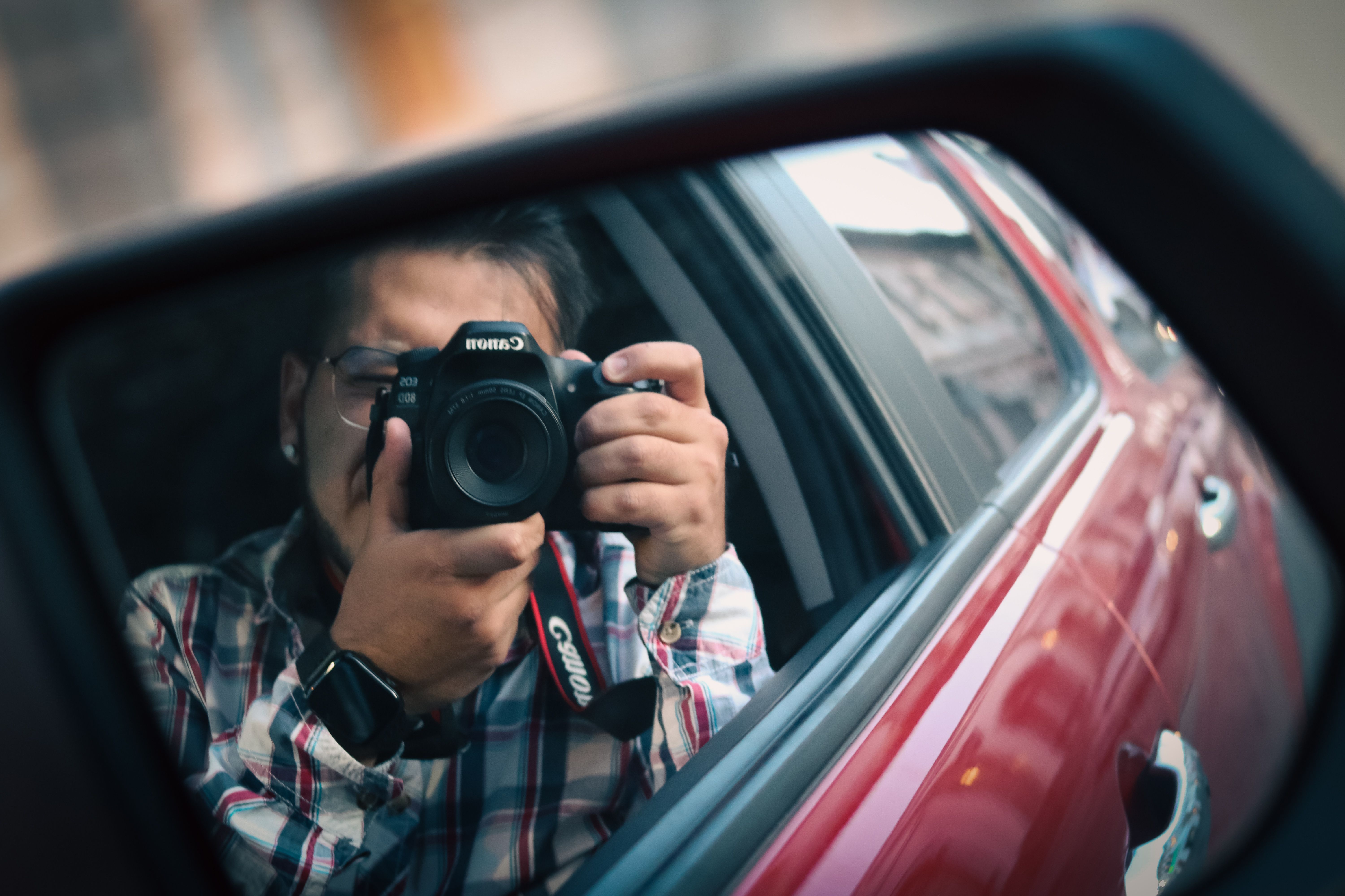 A man taking a photo in the side mirror of a car · Free Stock Photo