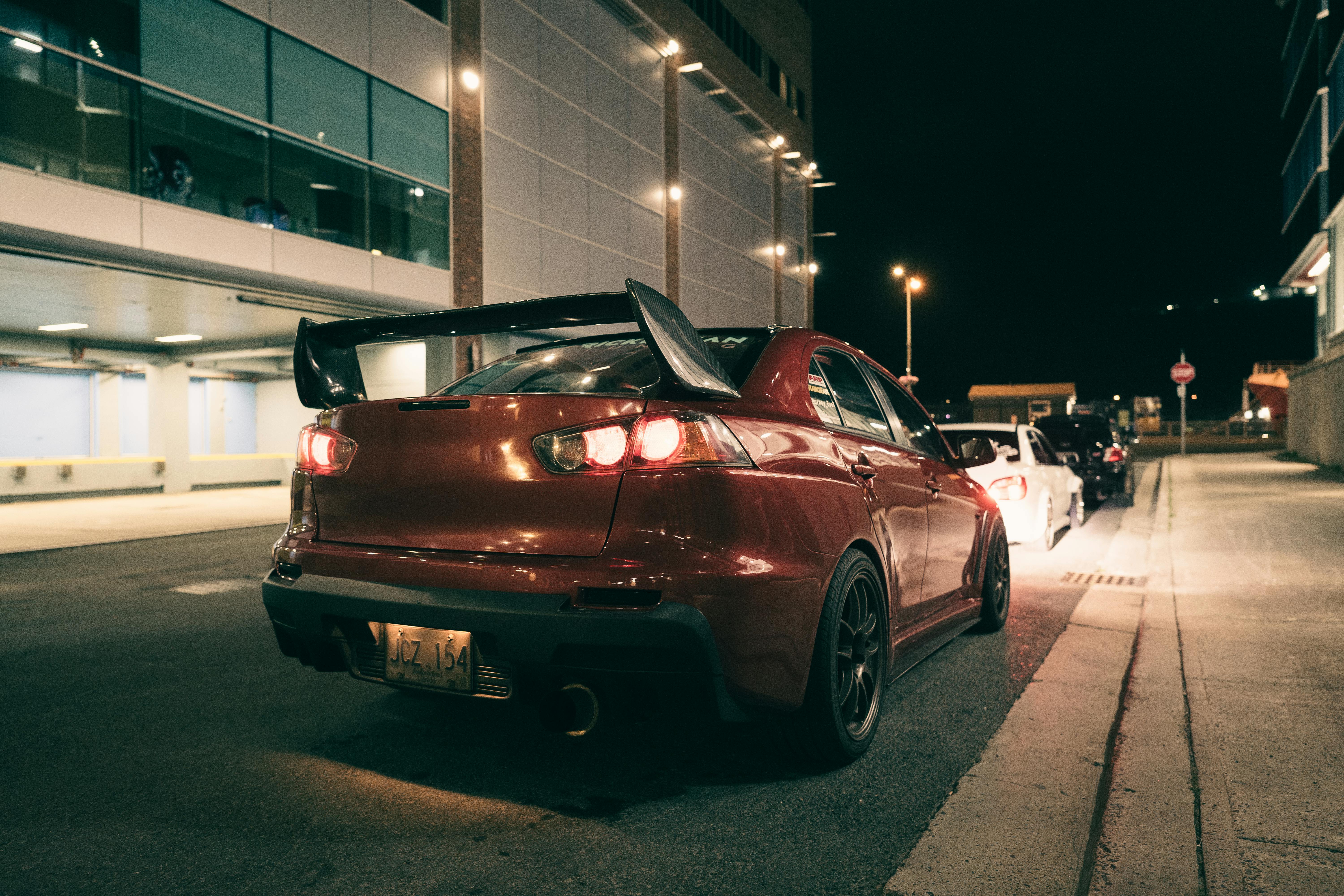 A red car parked at night on a street · Free Stock Photo