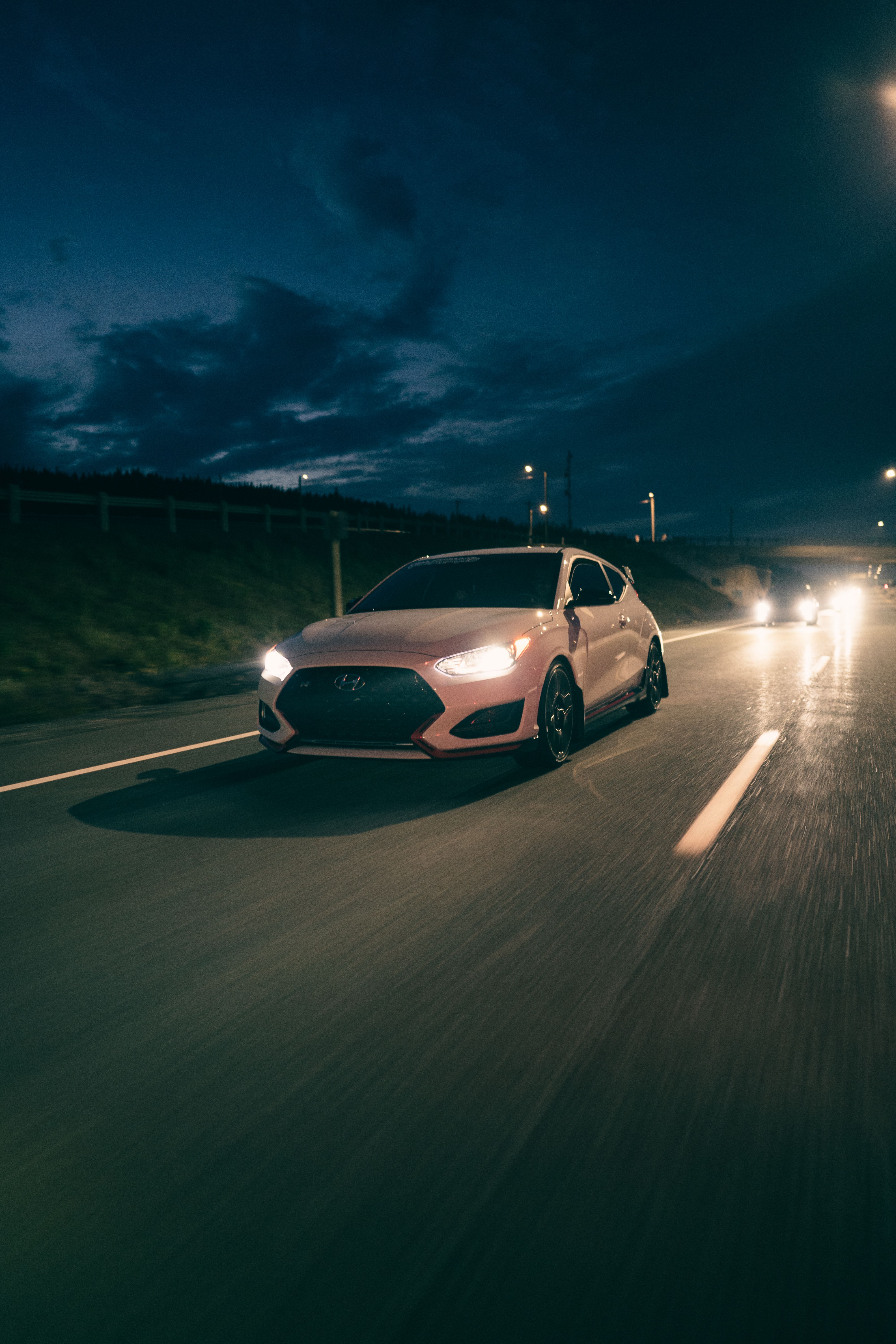 A pink car driving on the road at night · Free Stock Photo