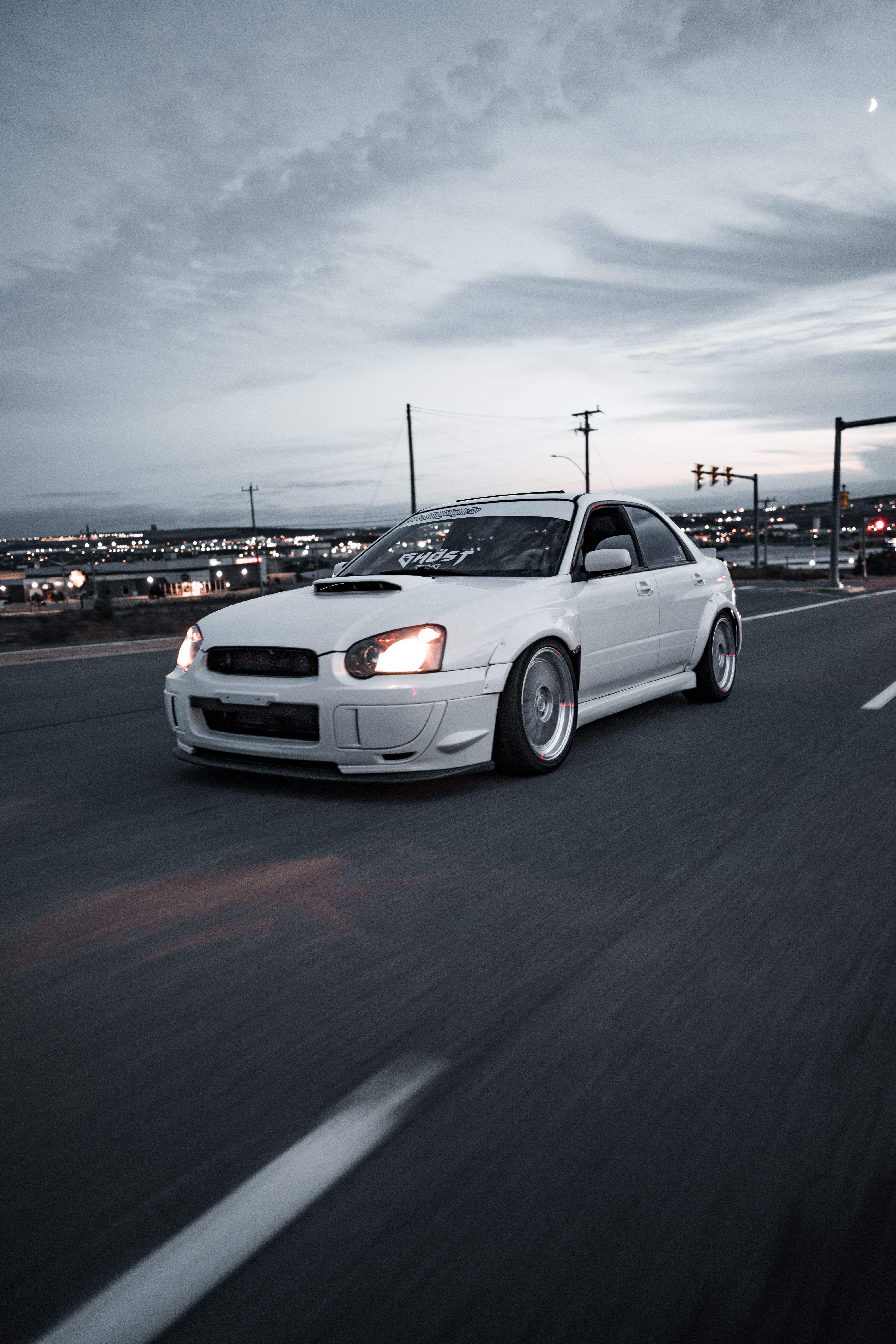 A white car driving down the road at night · Free Stock Photo