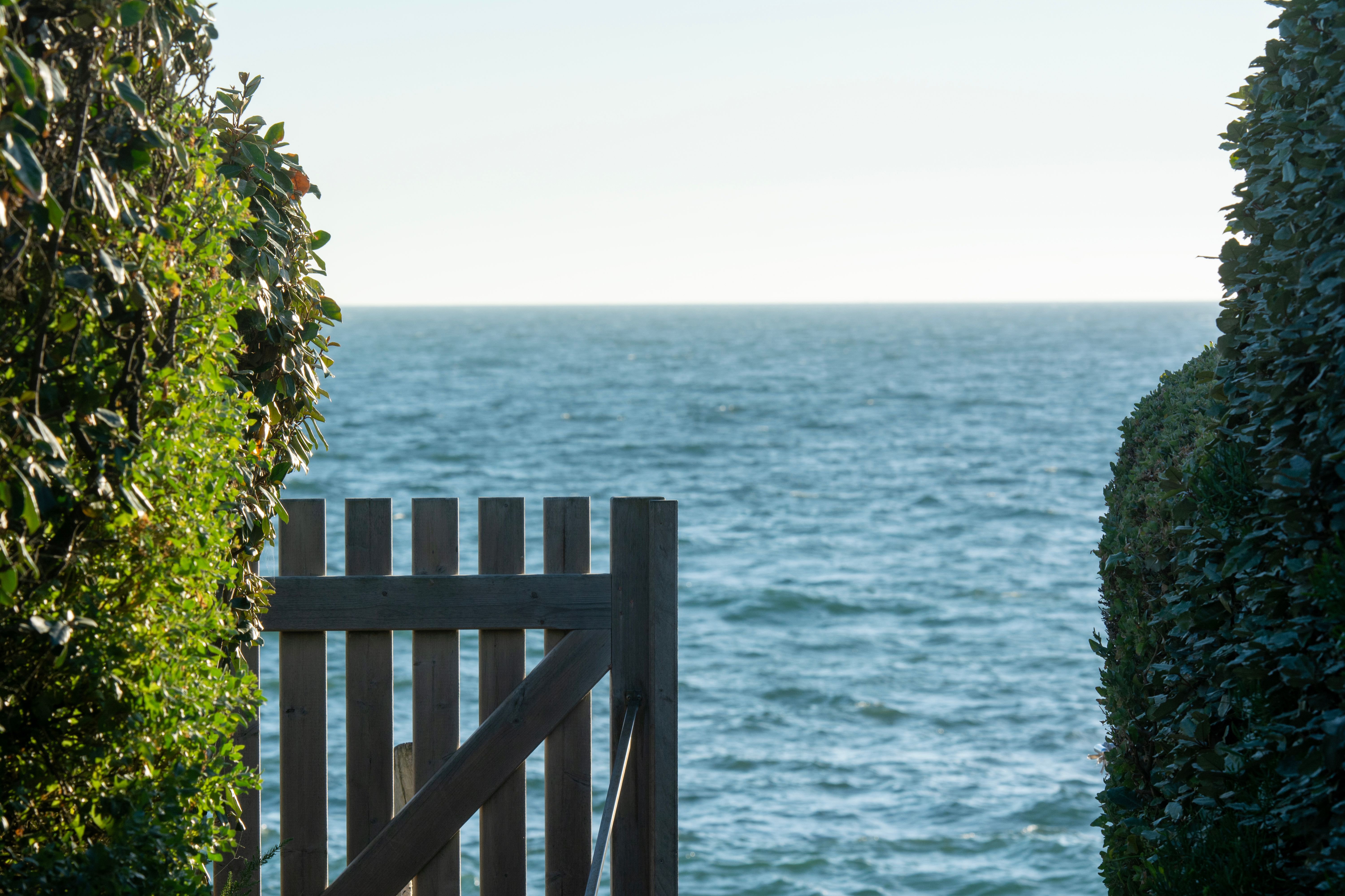 A gate leading to the ocean with a view of the water · Free Stock Photo