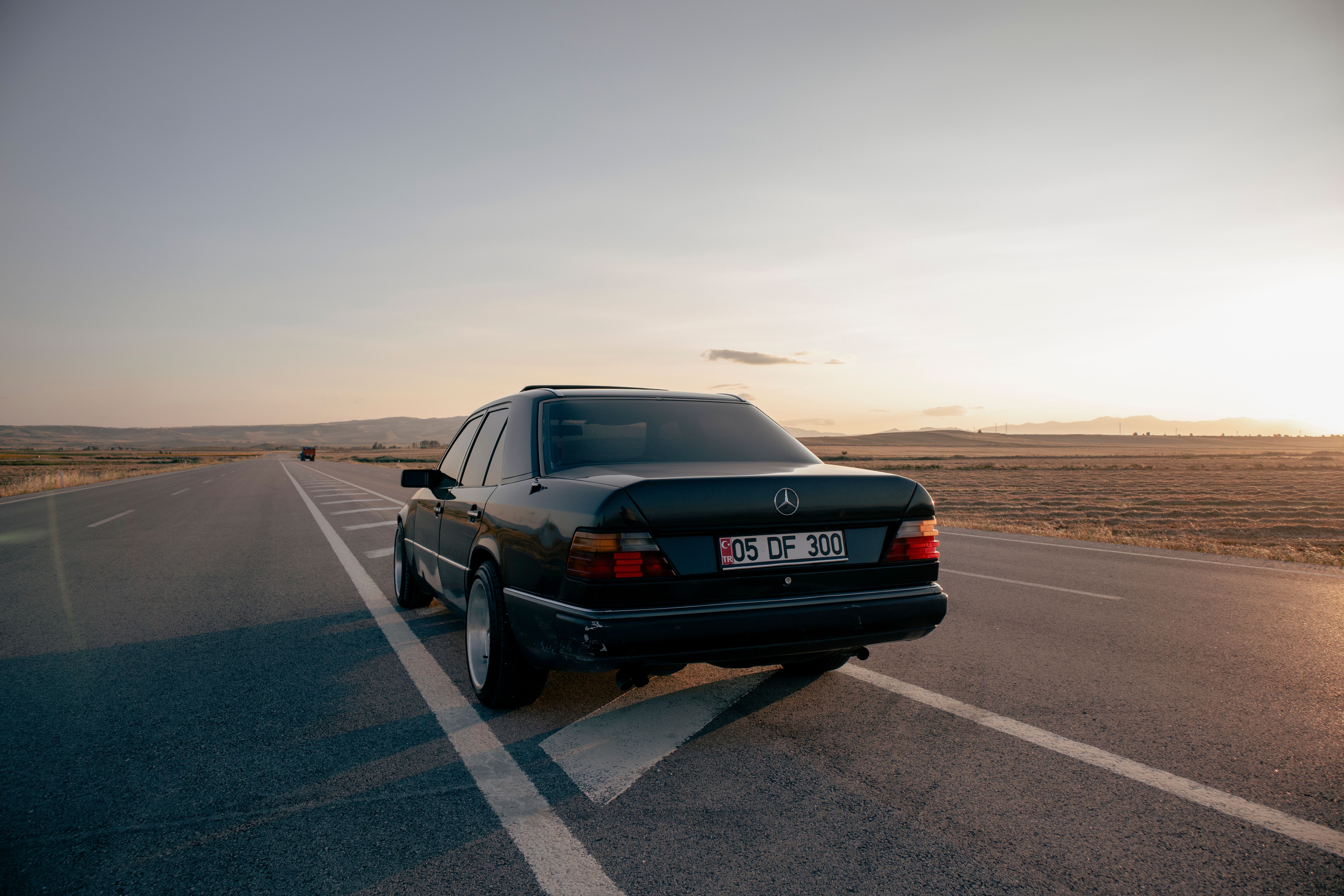 A black car driving down a road at sunset · Free Stock Photo
