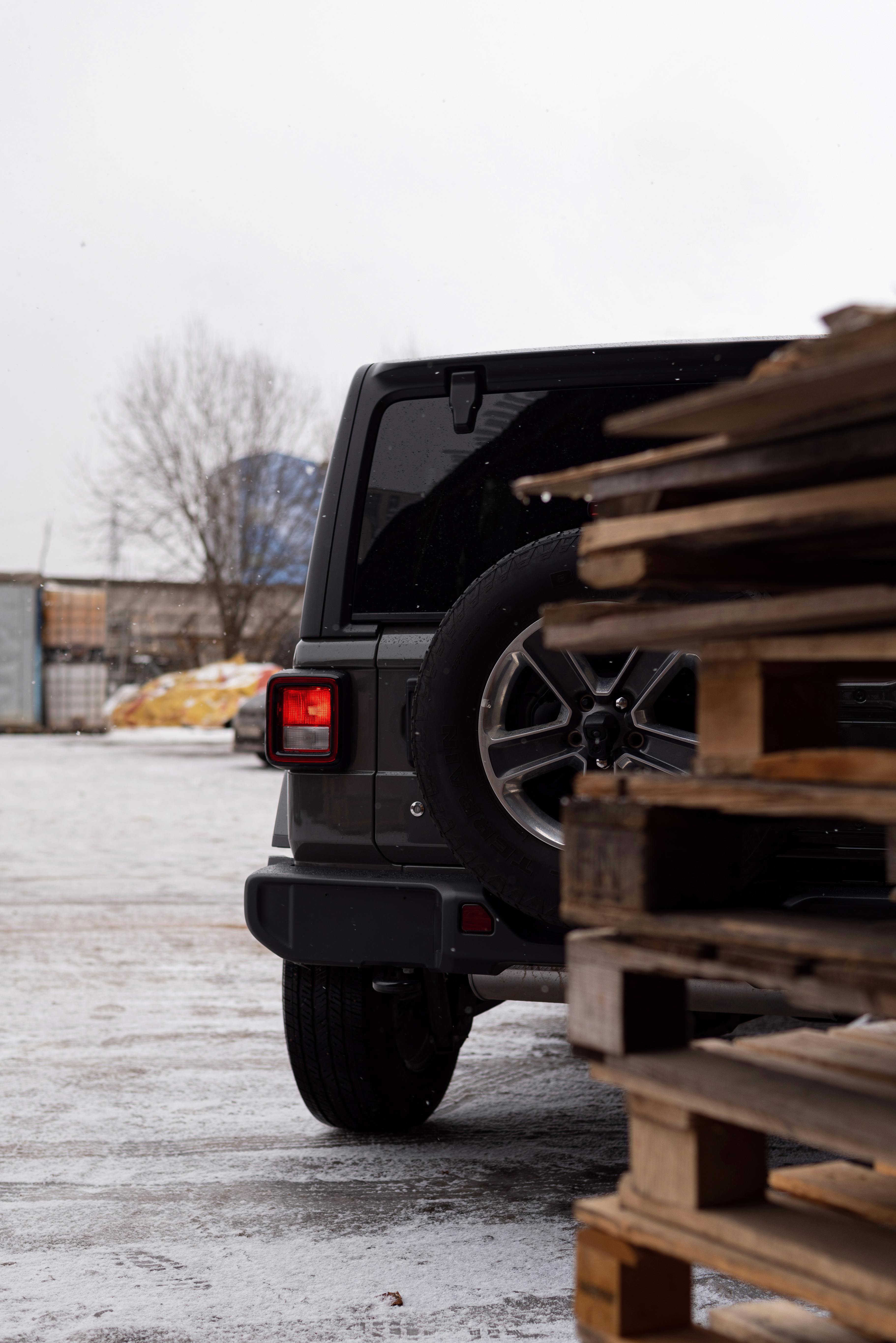A jeep parked in front of a stack of pallets · Free Stock Photo