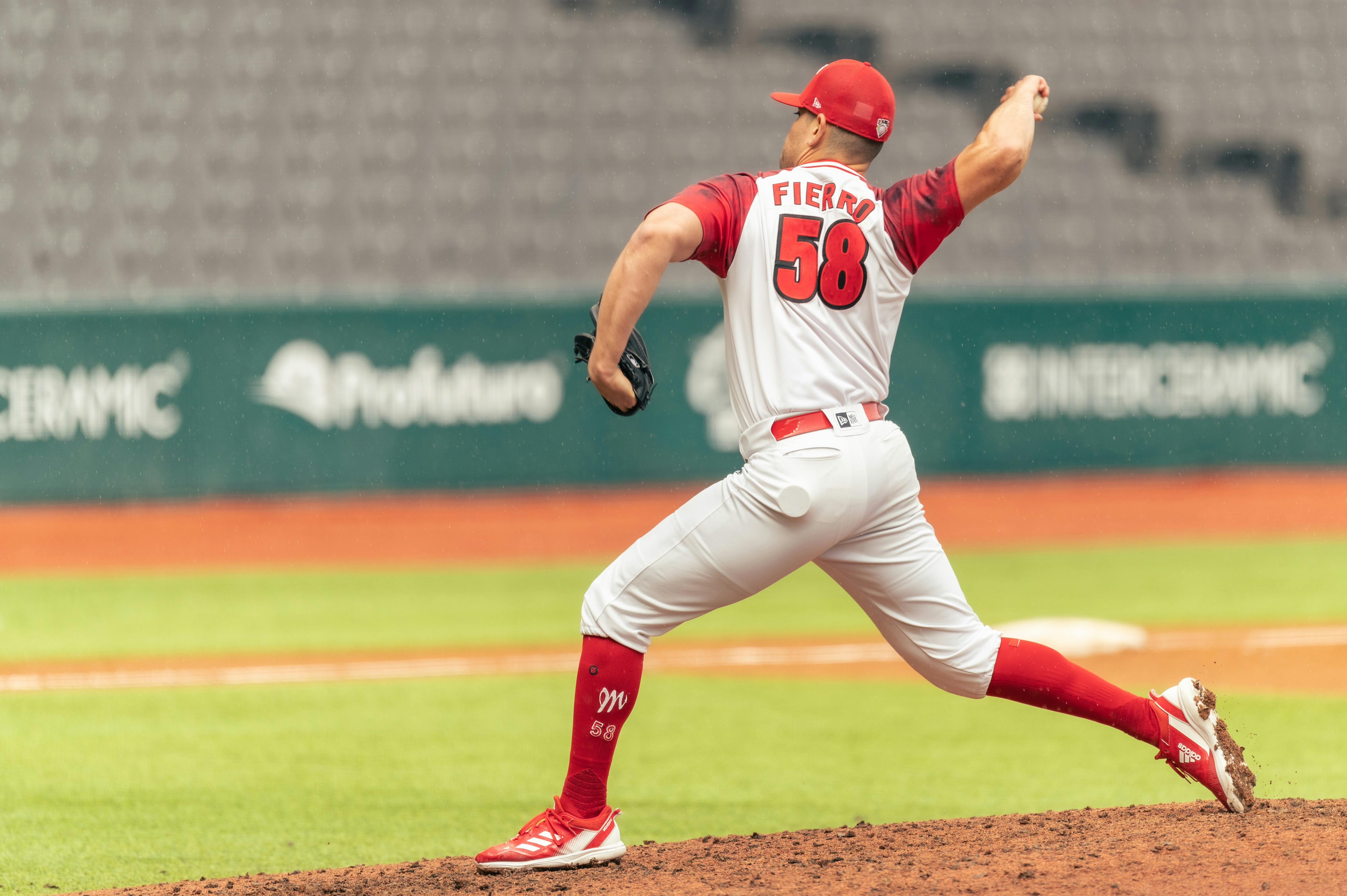A baseball player in red and white throwing a pitch · Free Stock Photo